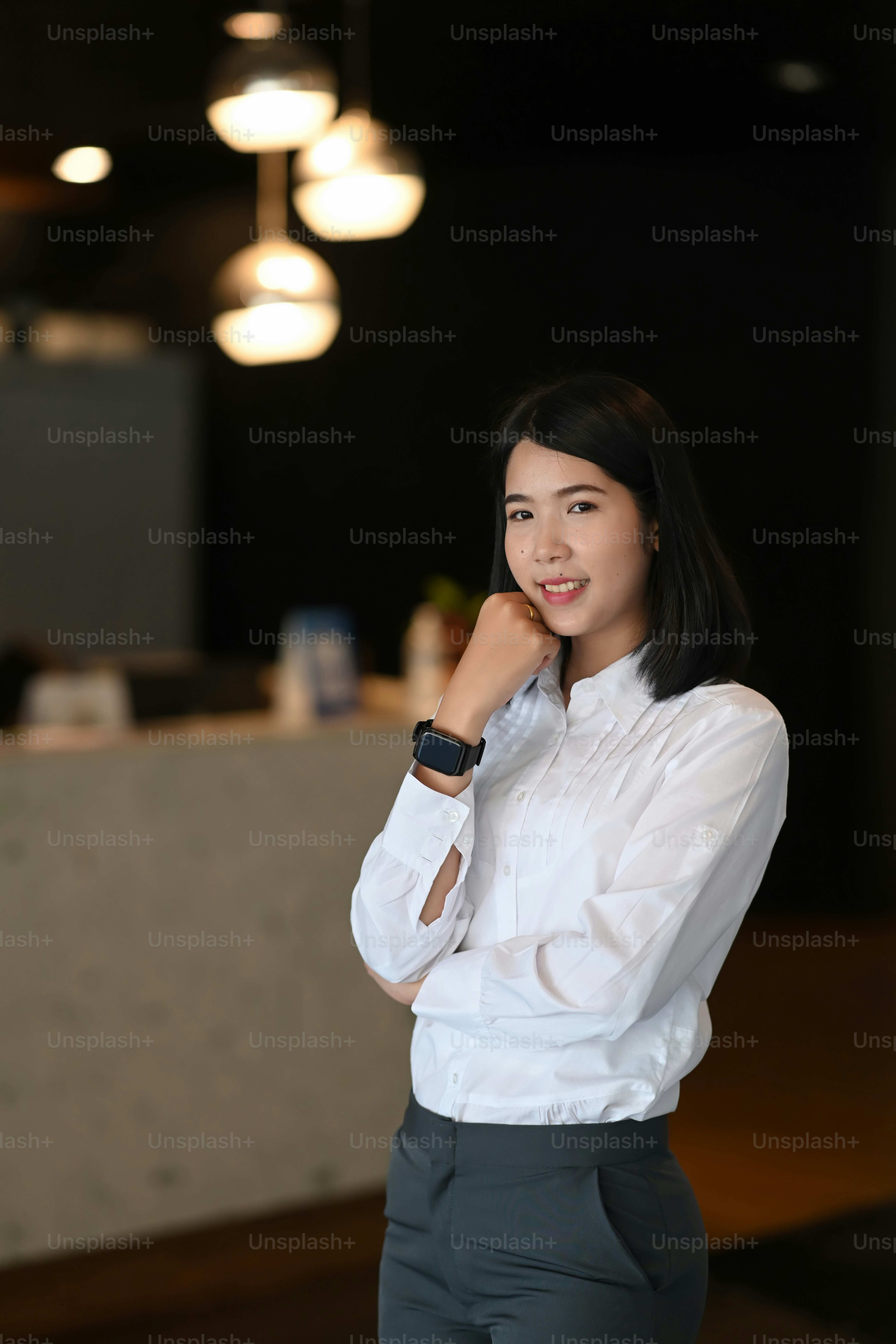 Confident businesswoman wearing smart watch standing in modern office ...