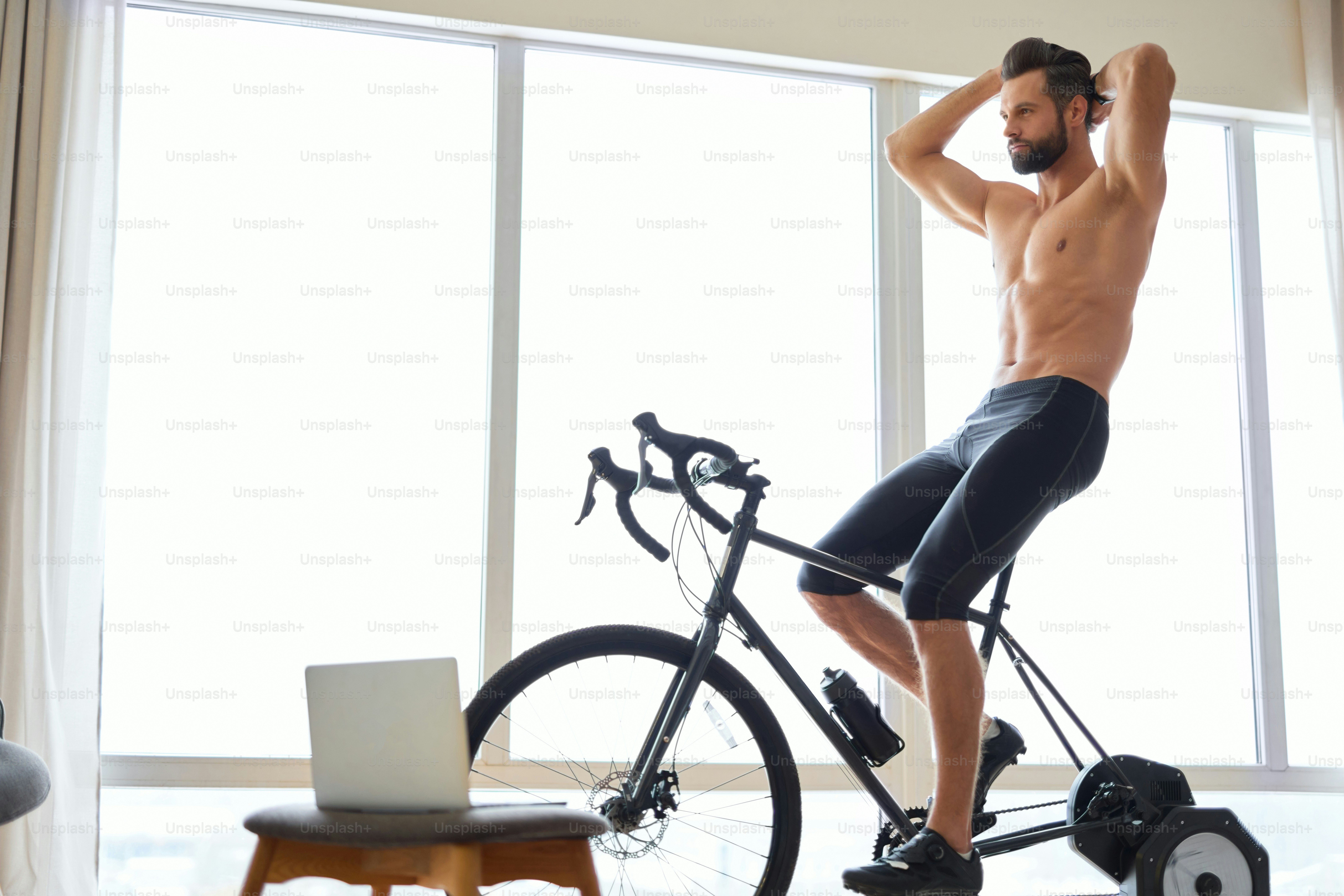 Handsome muscular gentleman with perfect body riding exercise bicycle ...