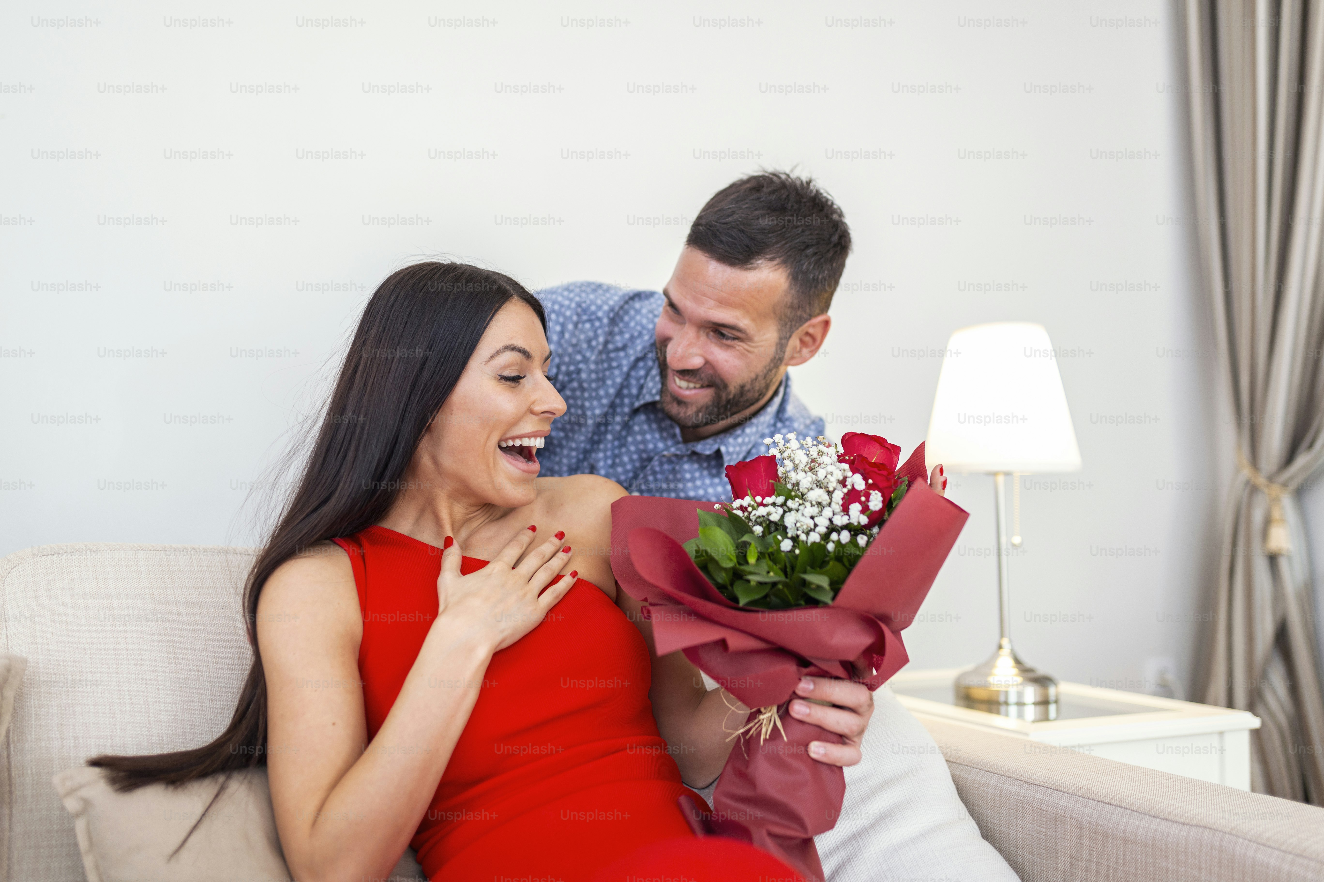Excited young woman receiving unexpected Bouquet of red roses from ...