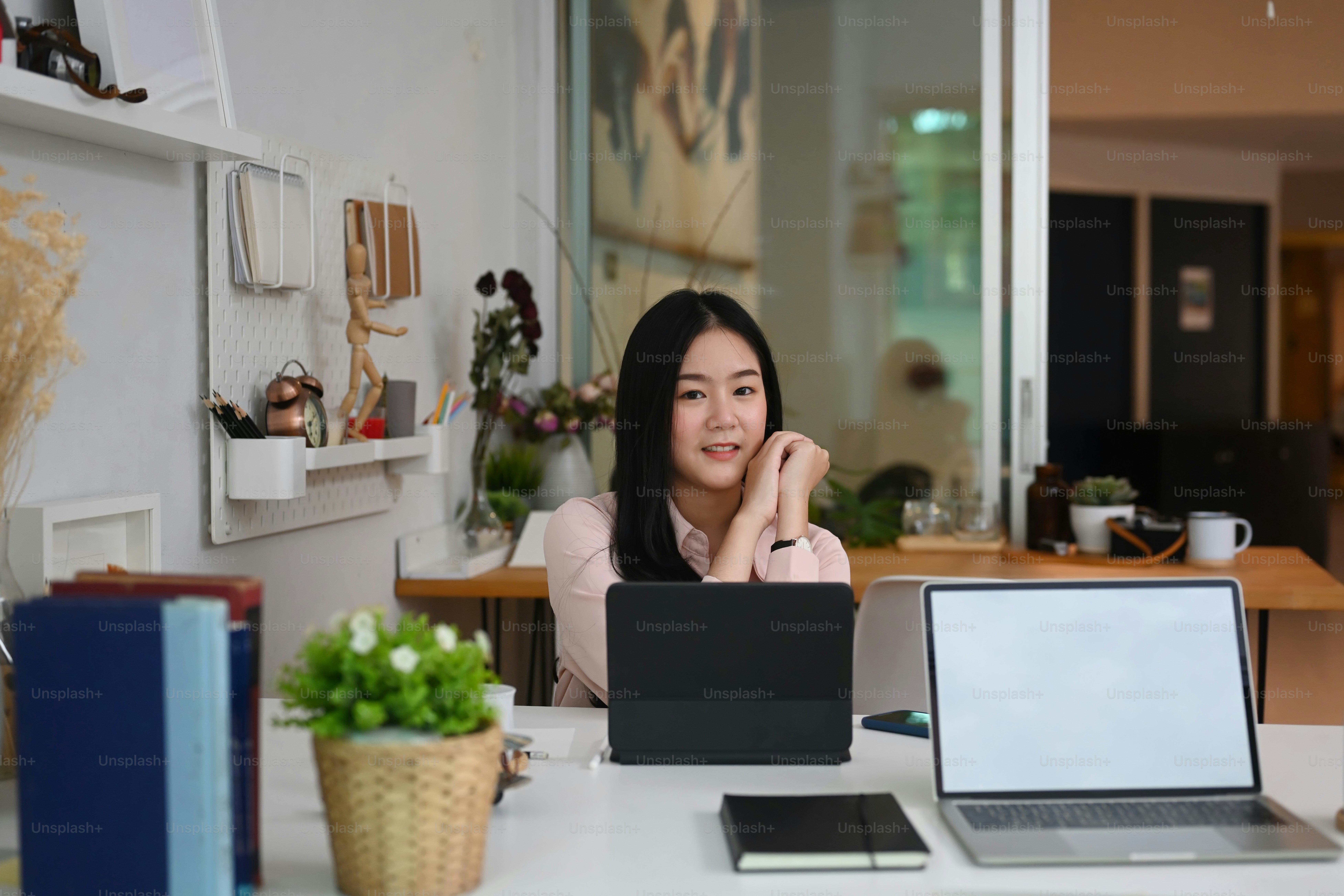 Portrait of young female graphic designer sitting in front of her ...