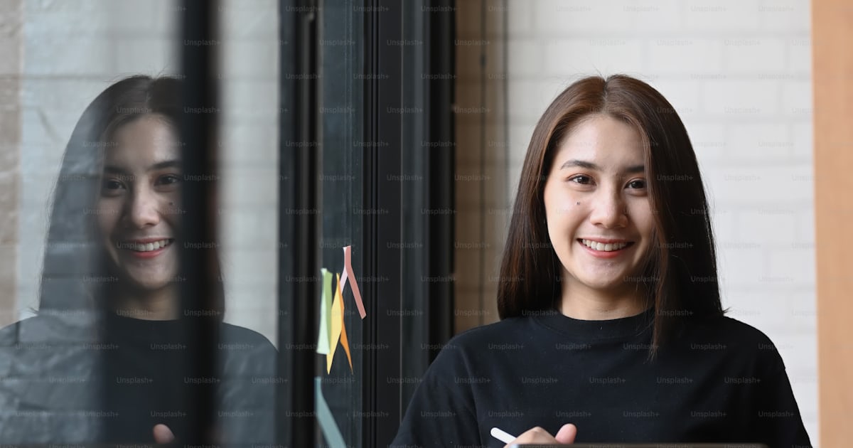 디지털 태블릿을 들고 사무실의 창문 근처에 서서 카메라를 향해 웃고 있는 젊은 사업가의 초상화 사진 Unsplash의 태국 이미지