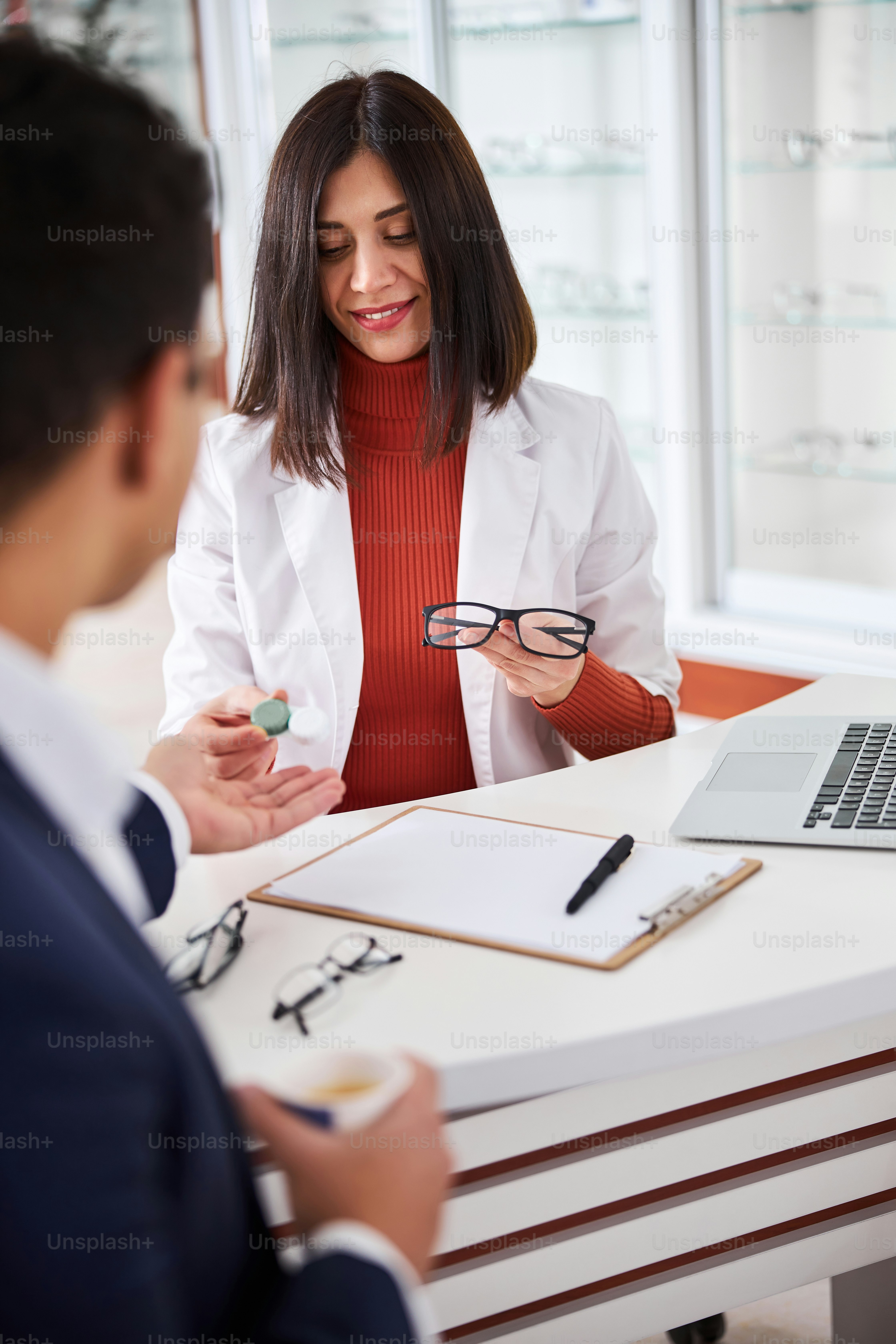 Smiling friendly professional female optical consultant assisting her ...
