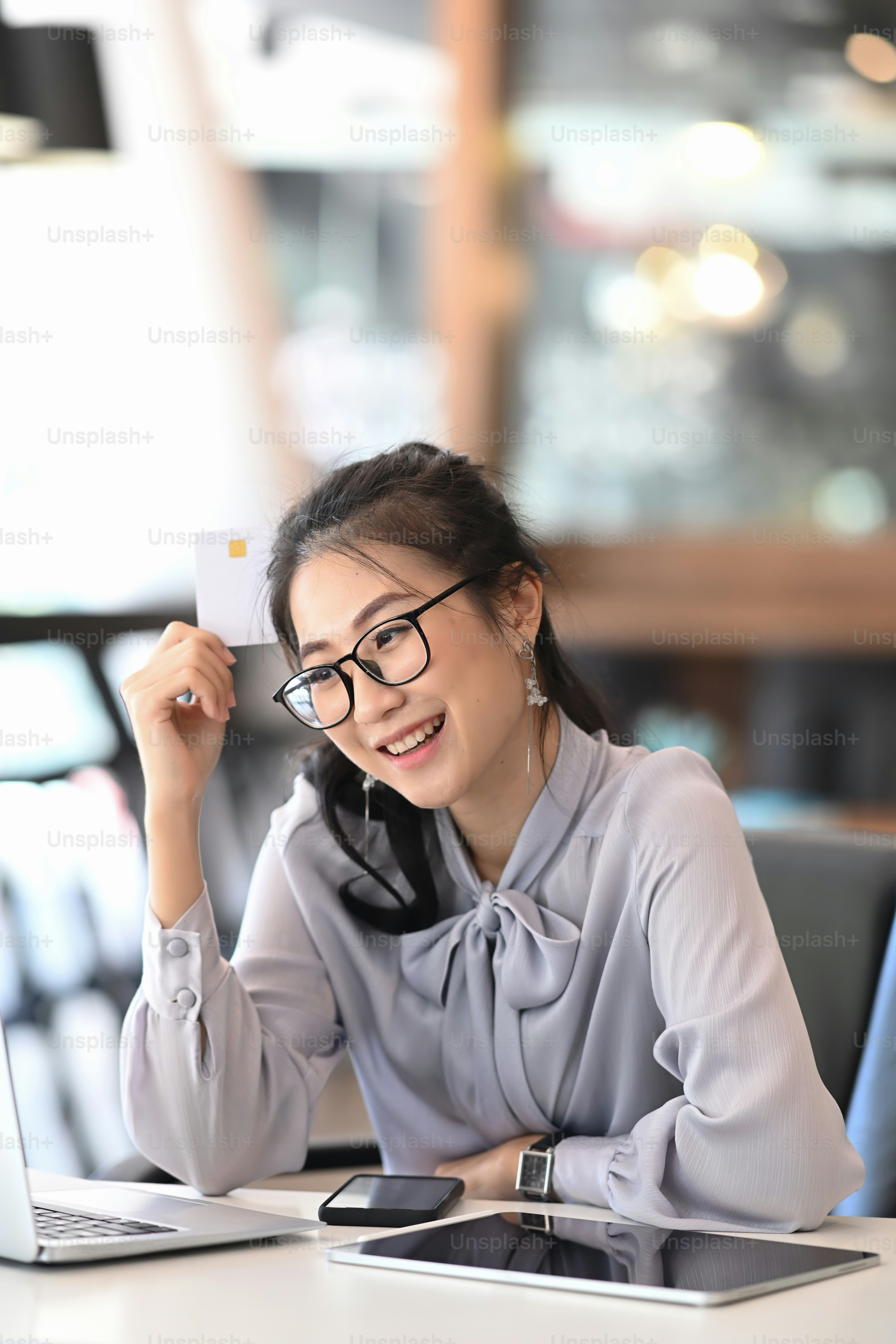 Portrait of cheerful young woman in eye glasses using laptop and ...