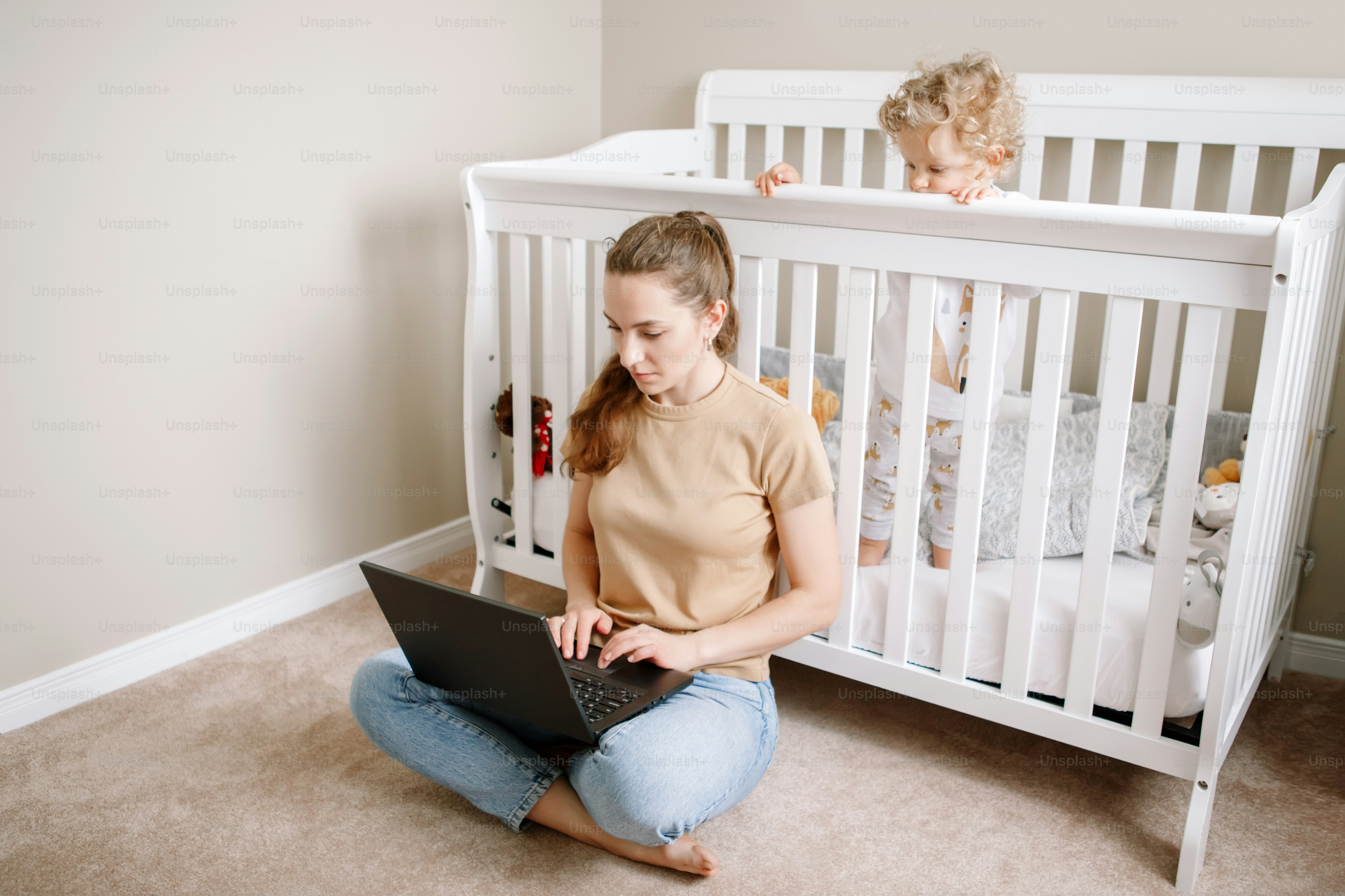 Madre caucásica con bebé trabajando en computadora portátil desde casa ...