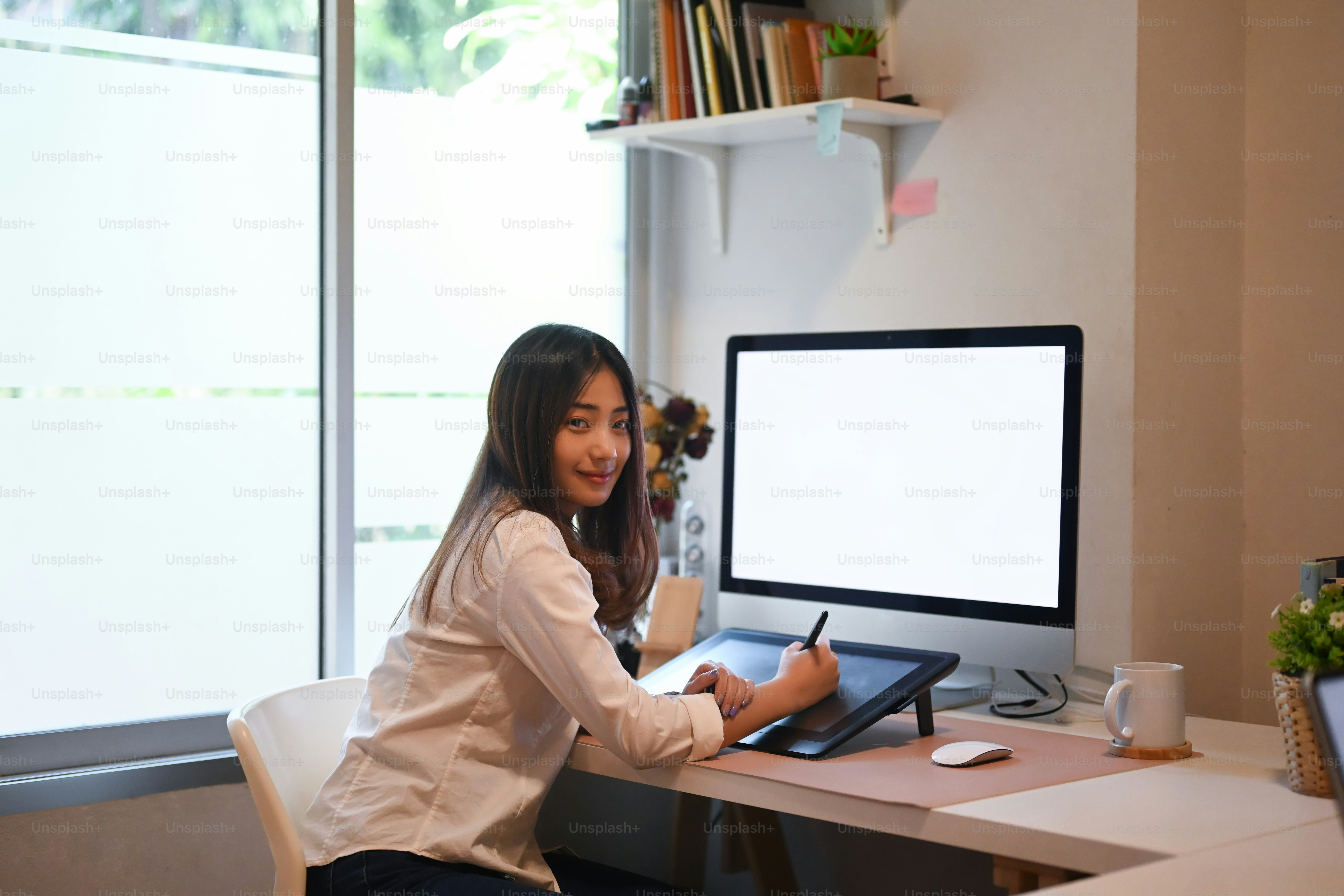 Young female graphic designer working on digitizer and computer at ...