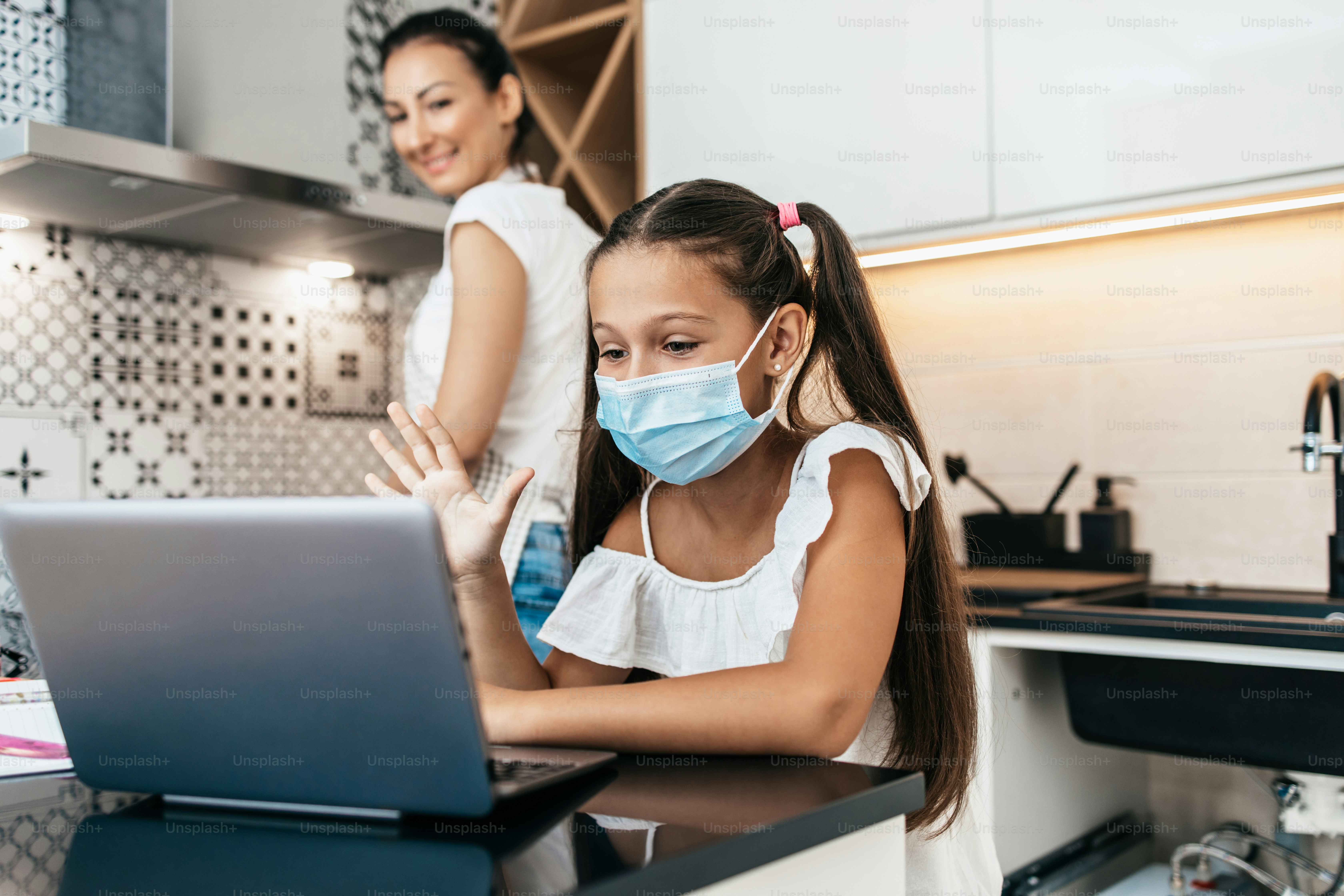 Young little girl having e-learning session during Covid-19 pandemic crisis lockdown or ...