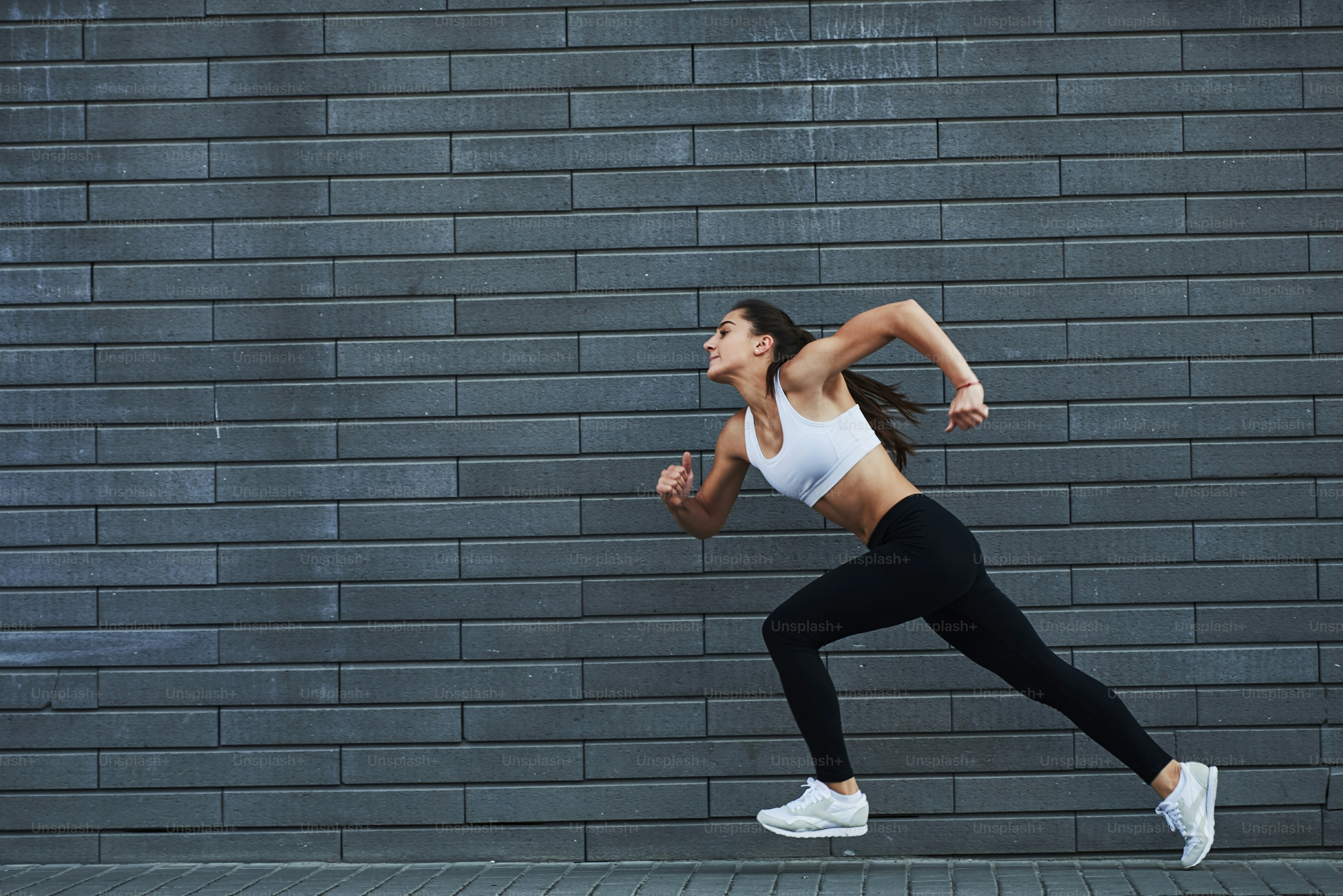 Running fast. Young sportive brunette with slim body shape against ...