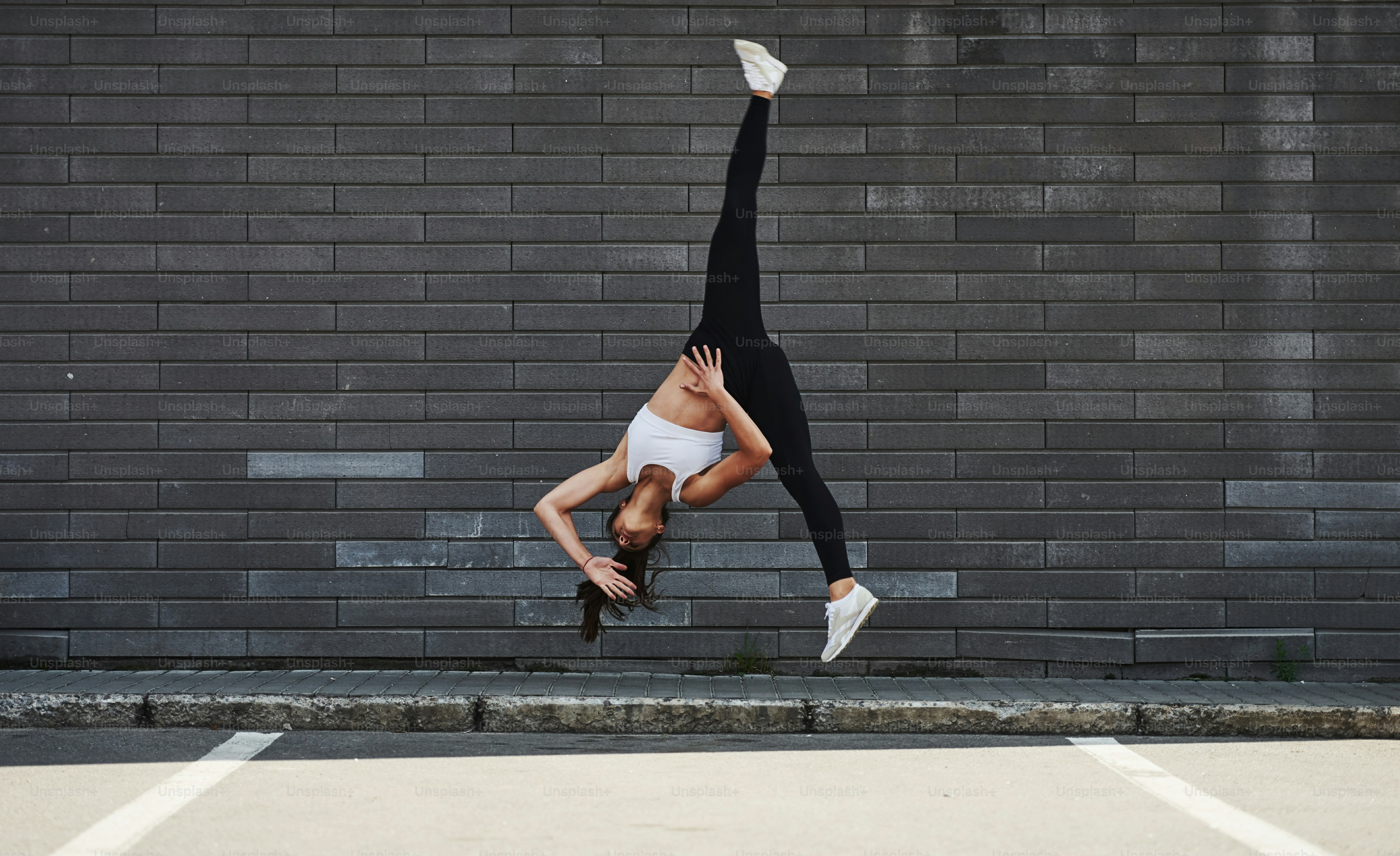 Doing crazy parkour and athletic stunts. Young sportive brunette with ...