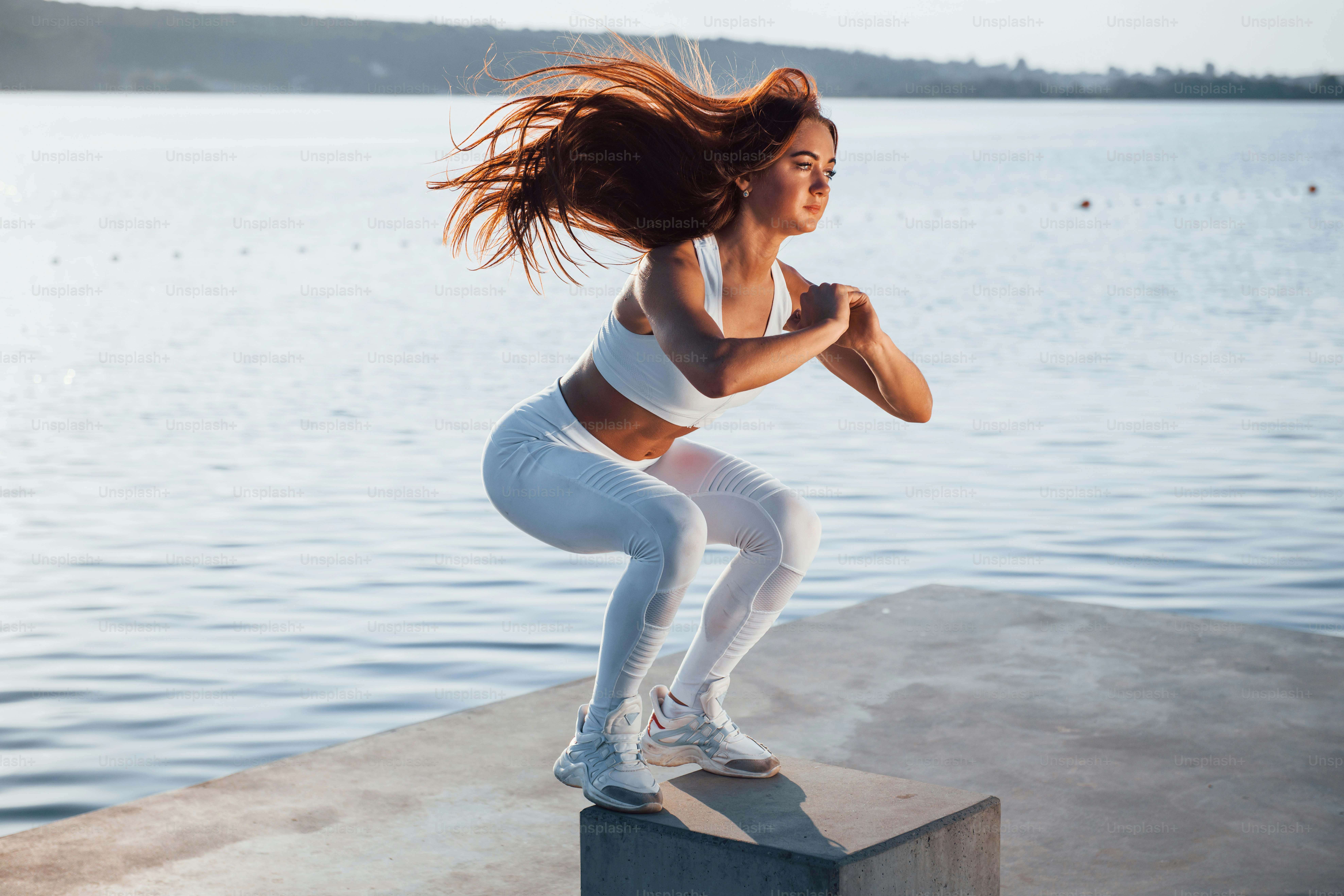 Doing squats on the cement cube. Shot of sportive woman doing fitness ...