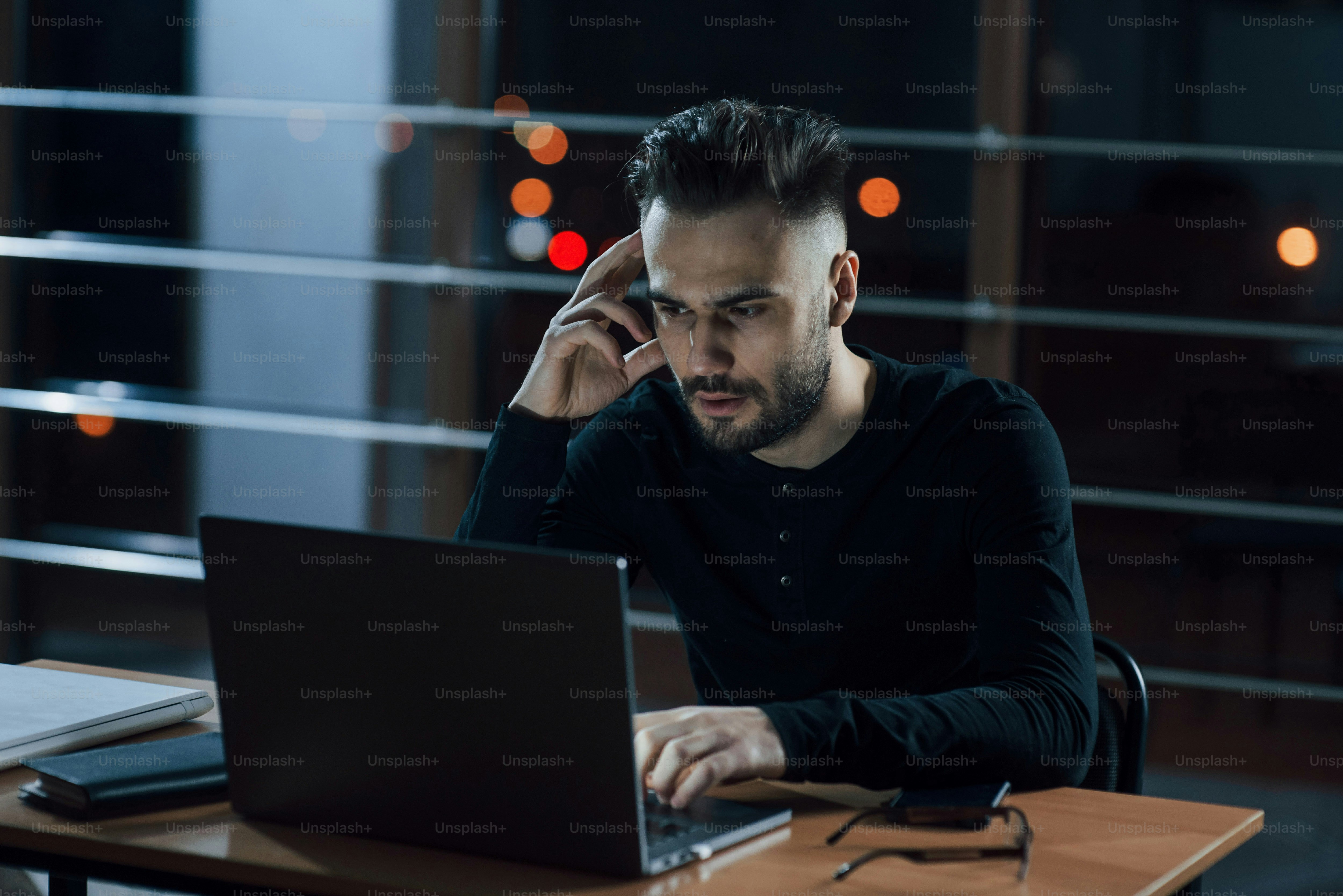 Want to sleep. Stylish young businessman works alone in the office at ...