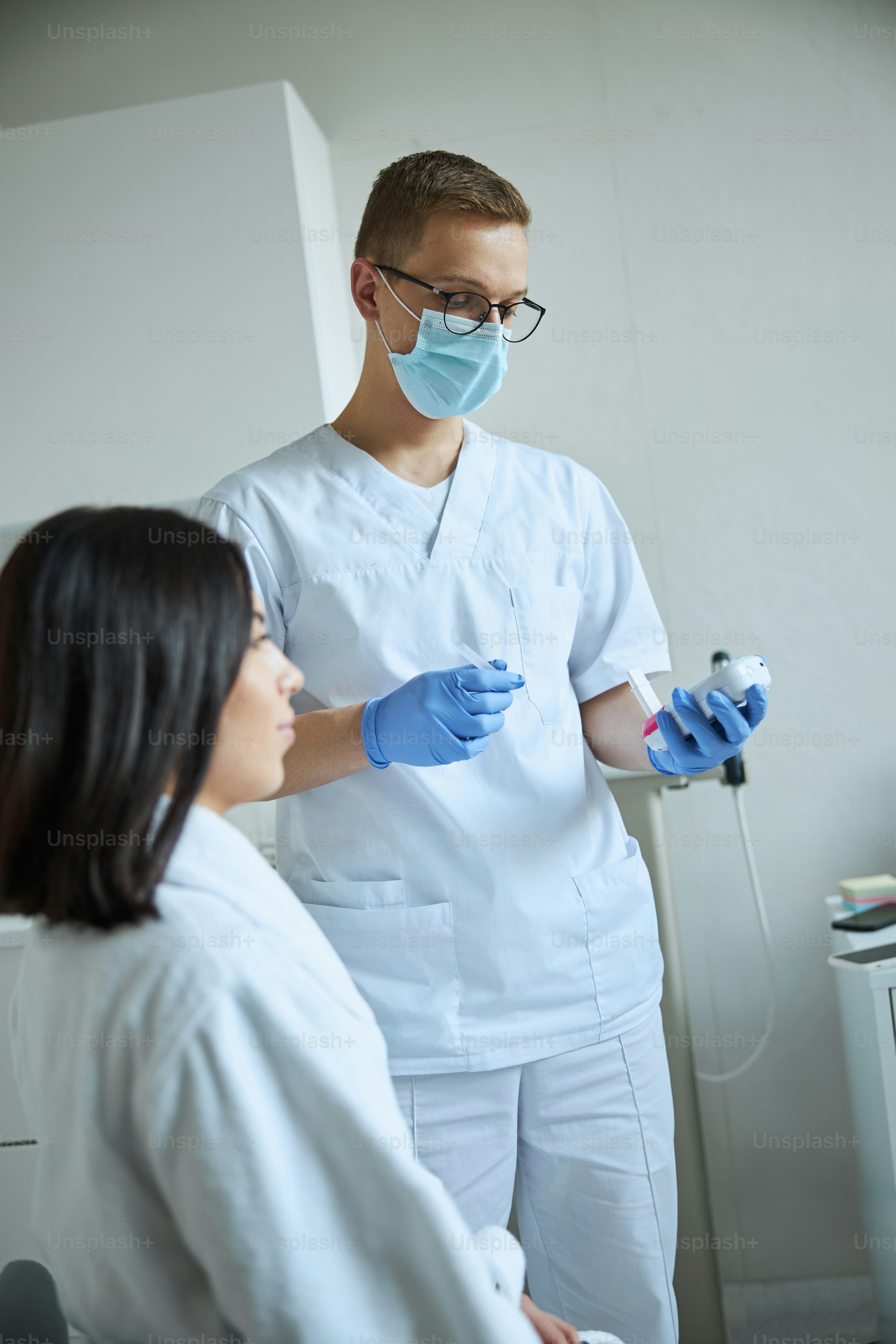 Focused doctor staring at the display of a handheld digital spirometer ...