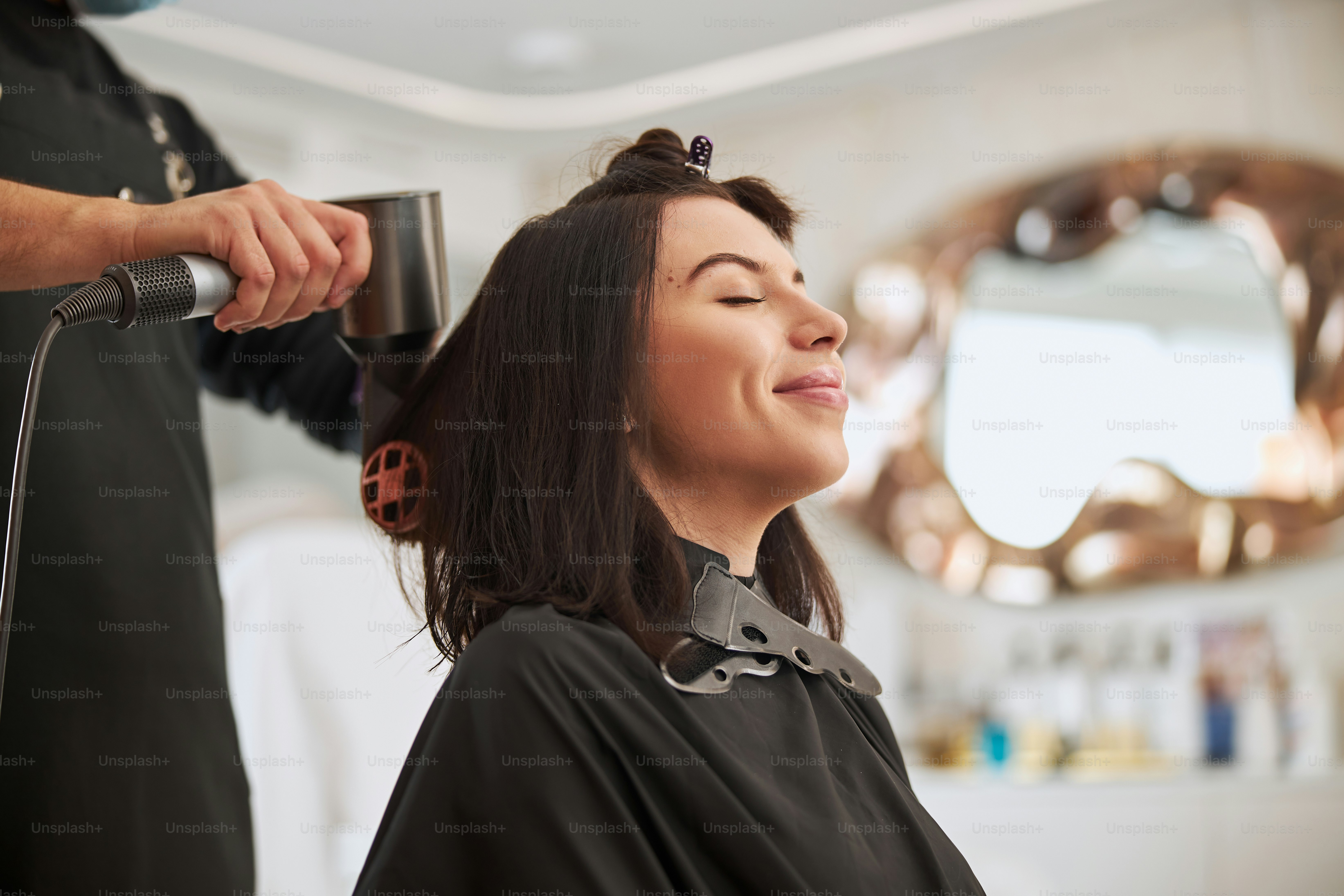 Smiling lovely woman with her eyes closed enjoying her hairstyling ...