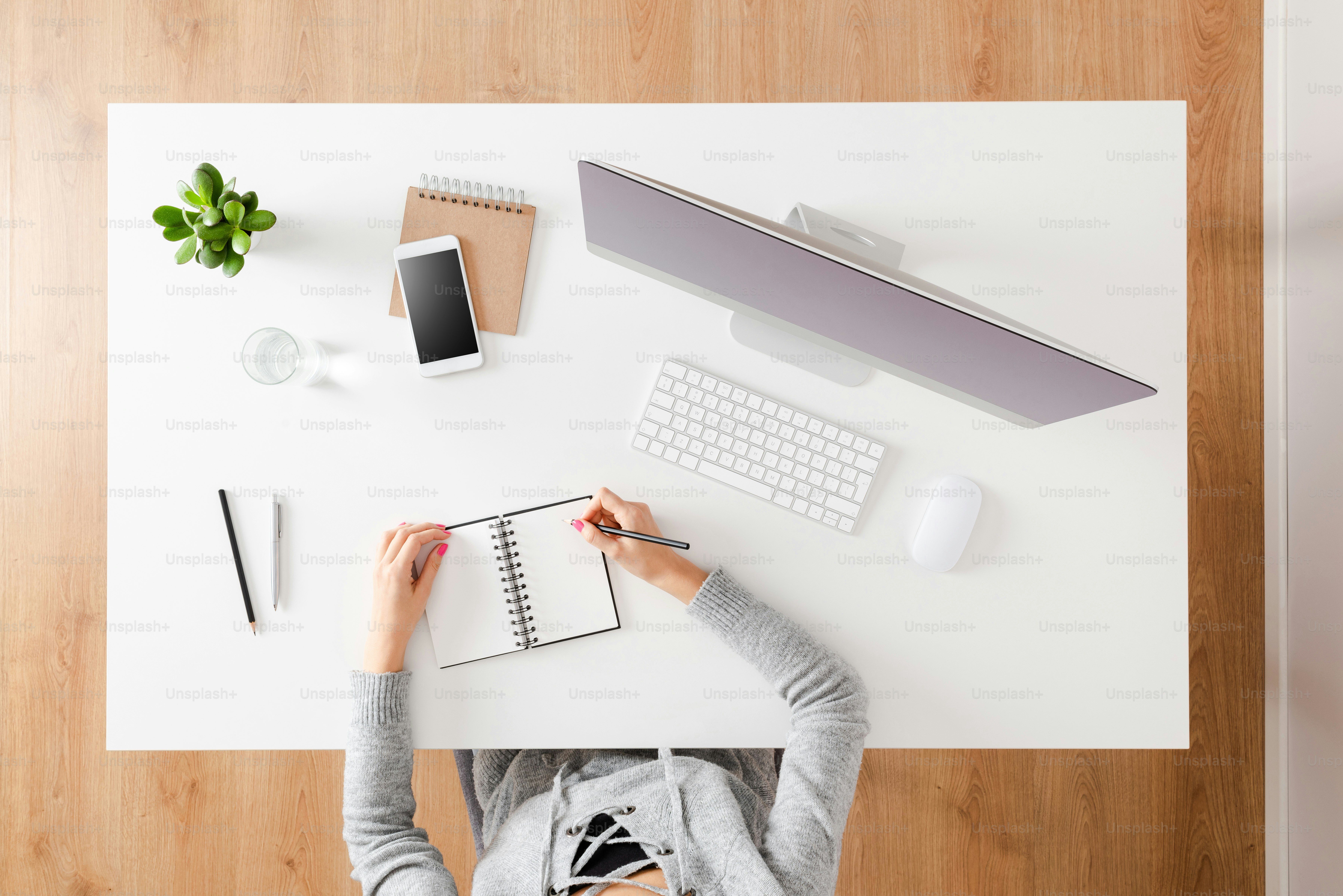 Foto zum Thema Frau schreibt in Notizbuch. Office-Desktop mit Computer ...