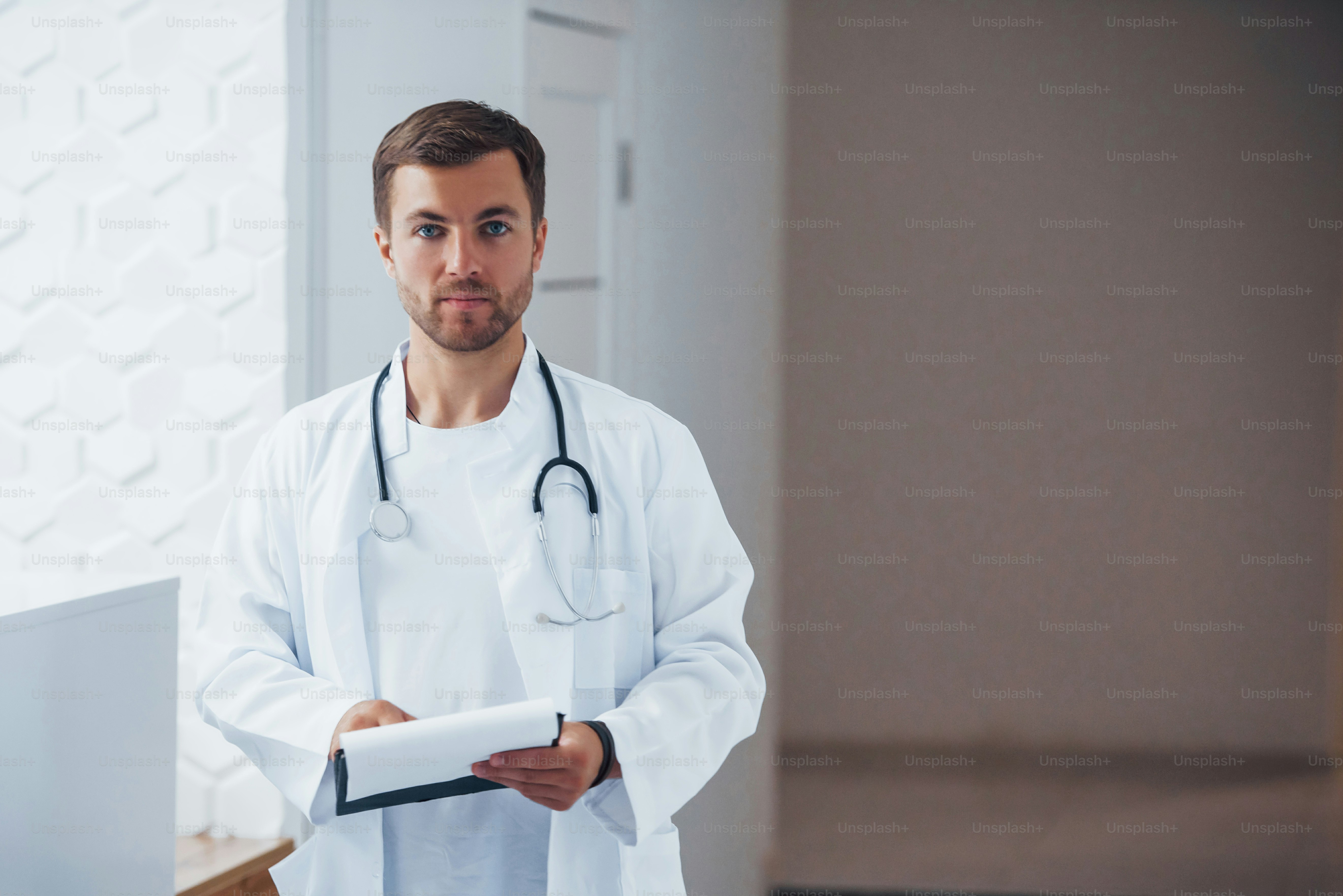 Portrait of confident male doctor with stethoscope and documents that ...