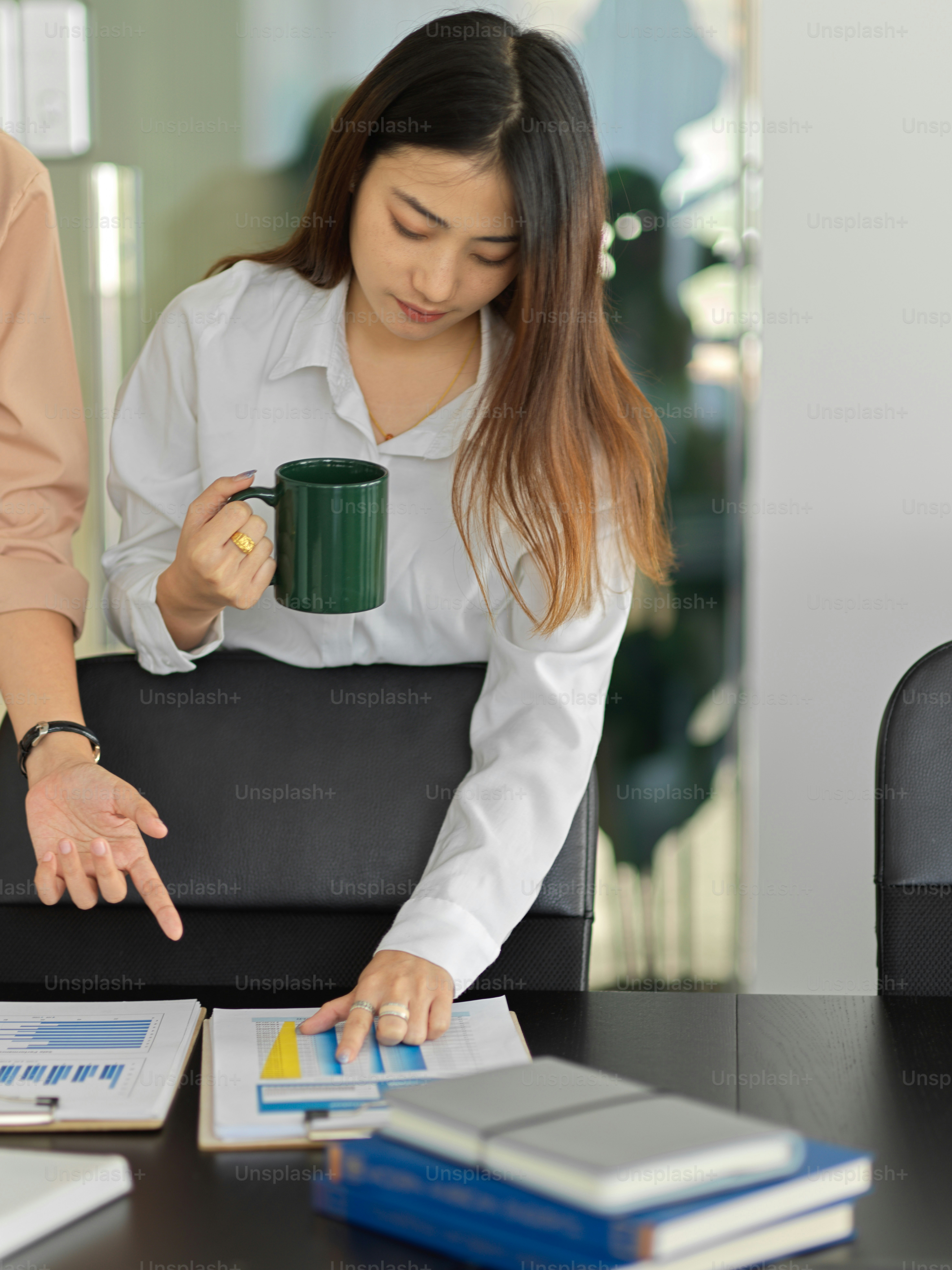 Portrait of female office worker holding coffee cup while consulting on ...