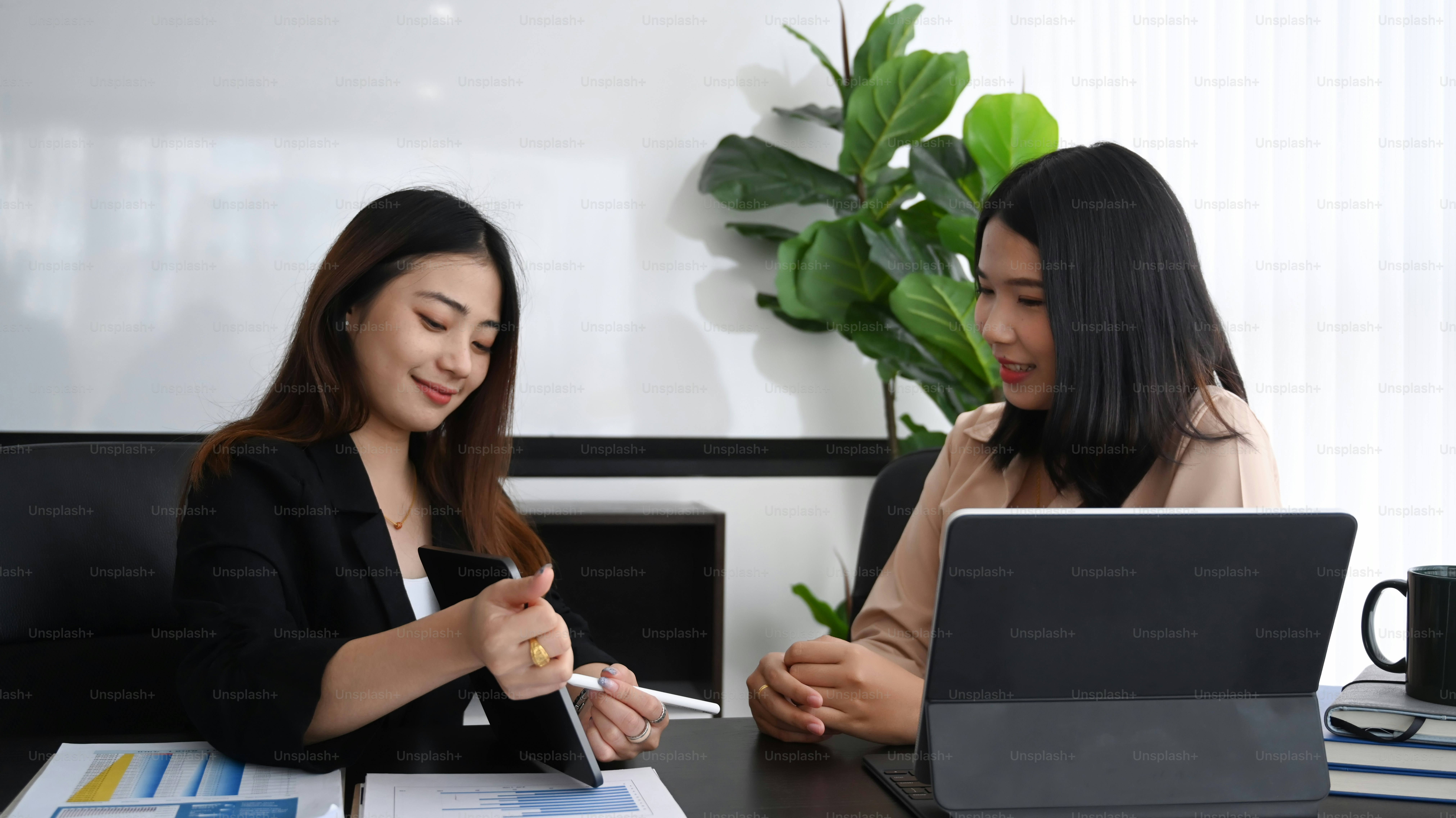 Businesswoman showing digital tablet and explaining to her colleague ...