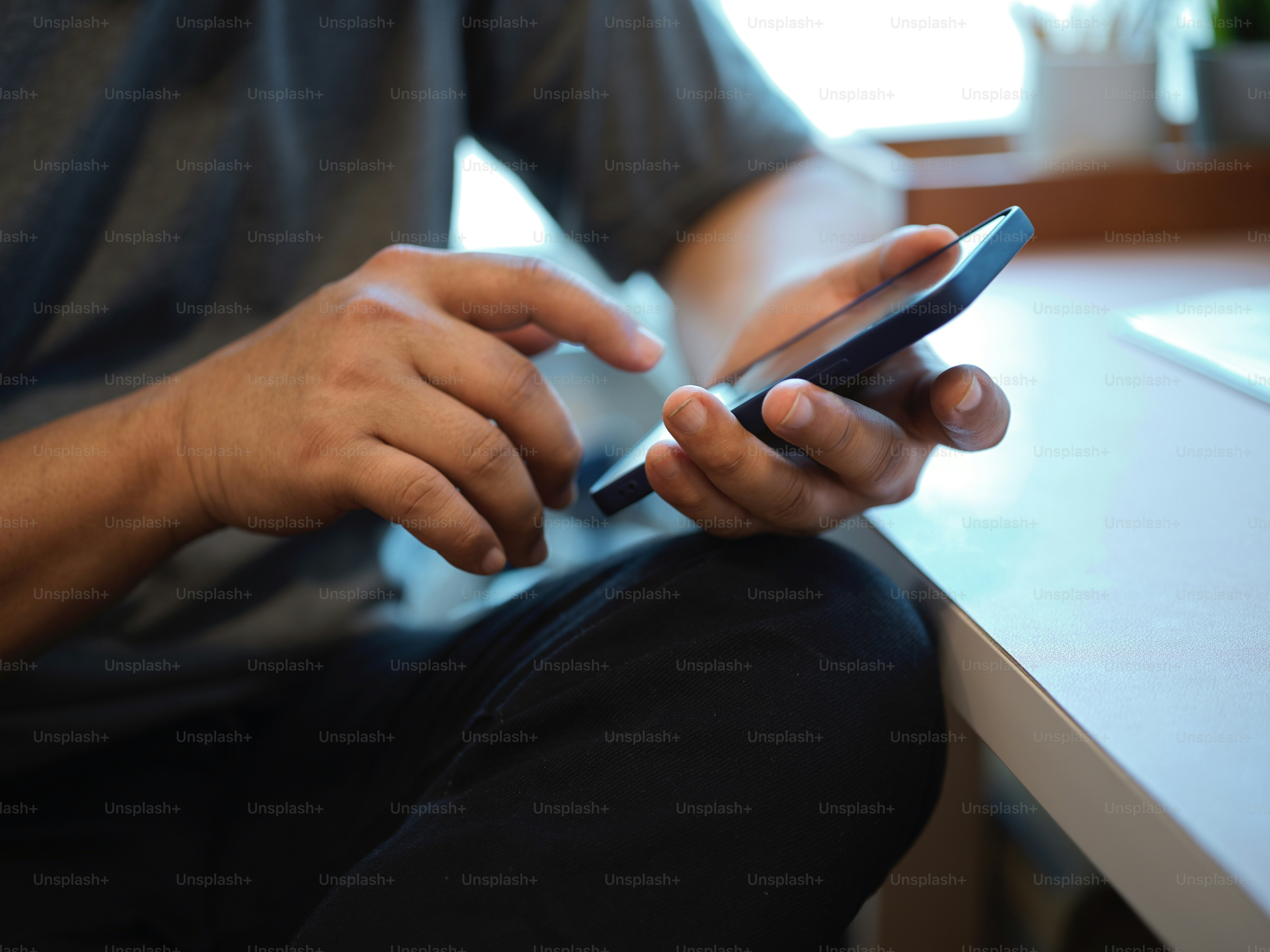Cropped shot of man using his smartphone in comfortable workspace photo ...