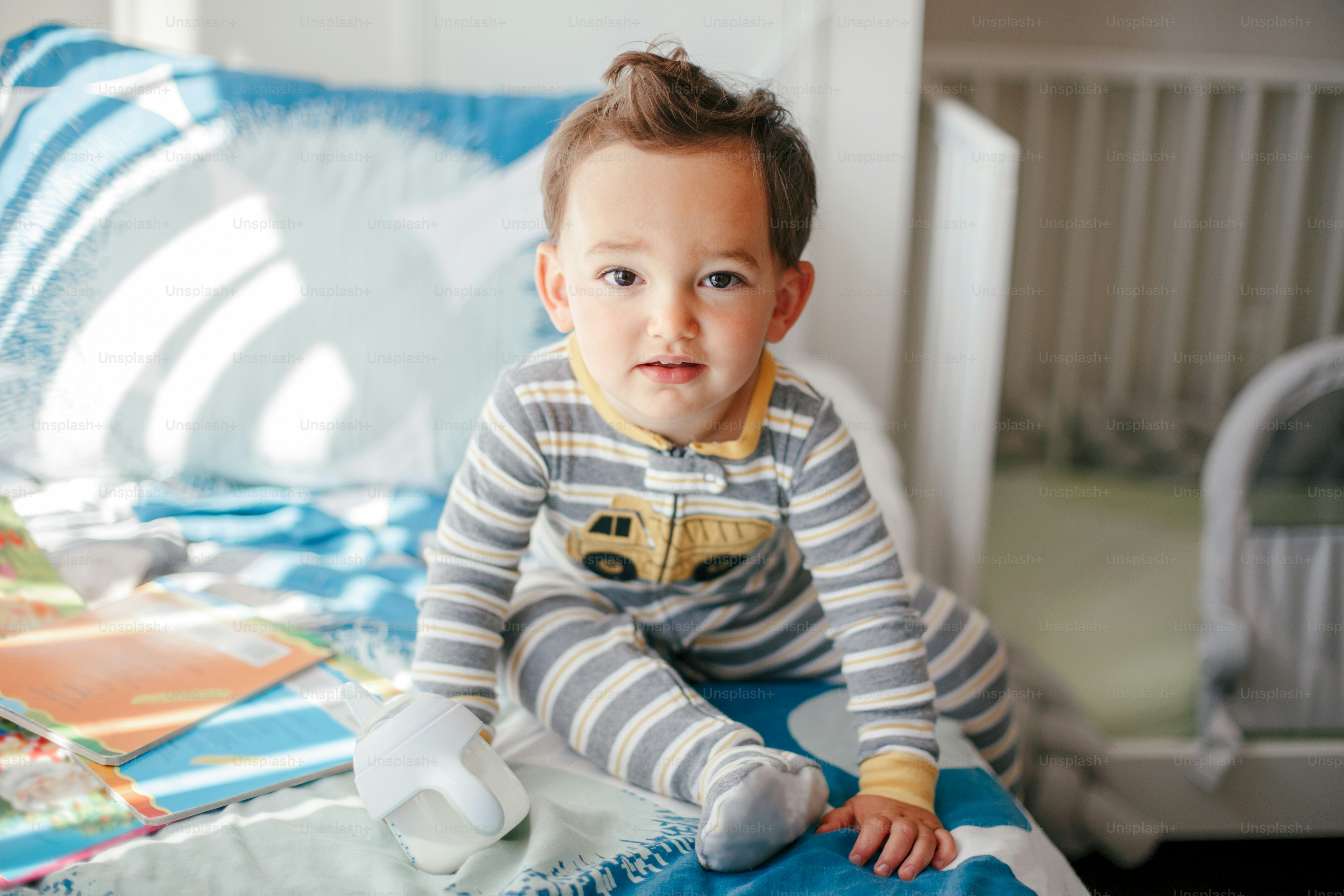 Lindo adorable niño caucásico sentado en una cama bebiendo leche del ...