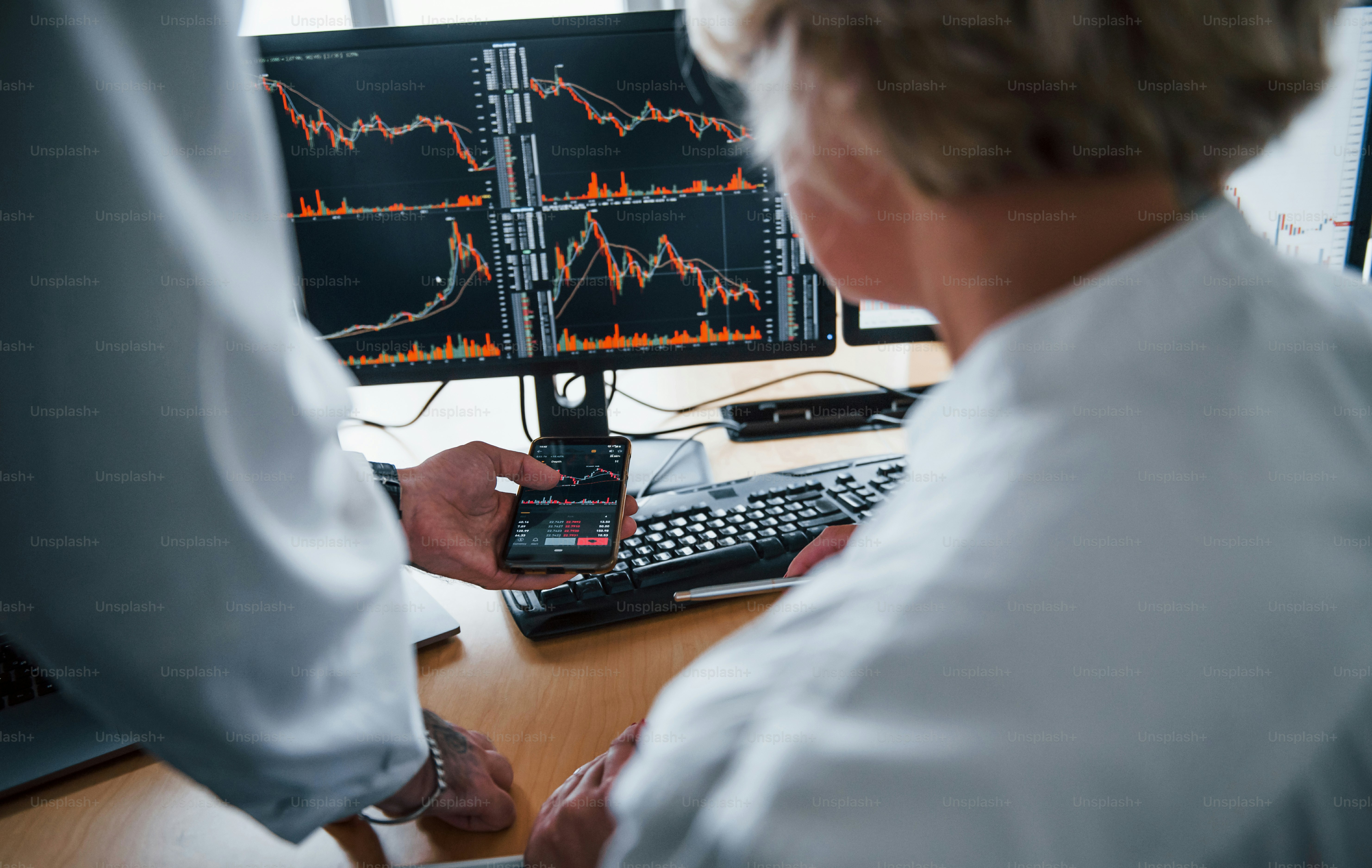 Two stockbrokers in formal clothes works in the office with financial ...