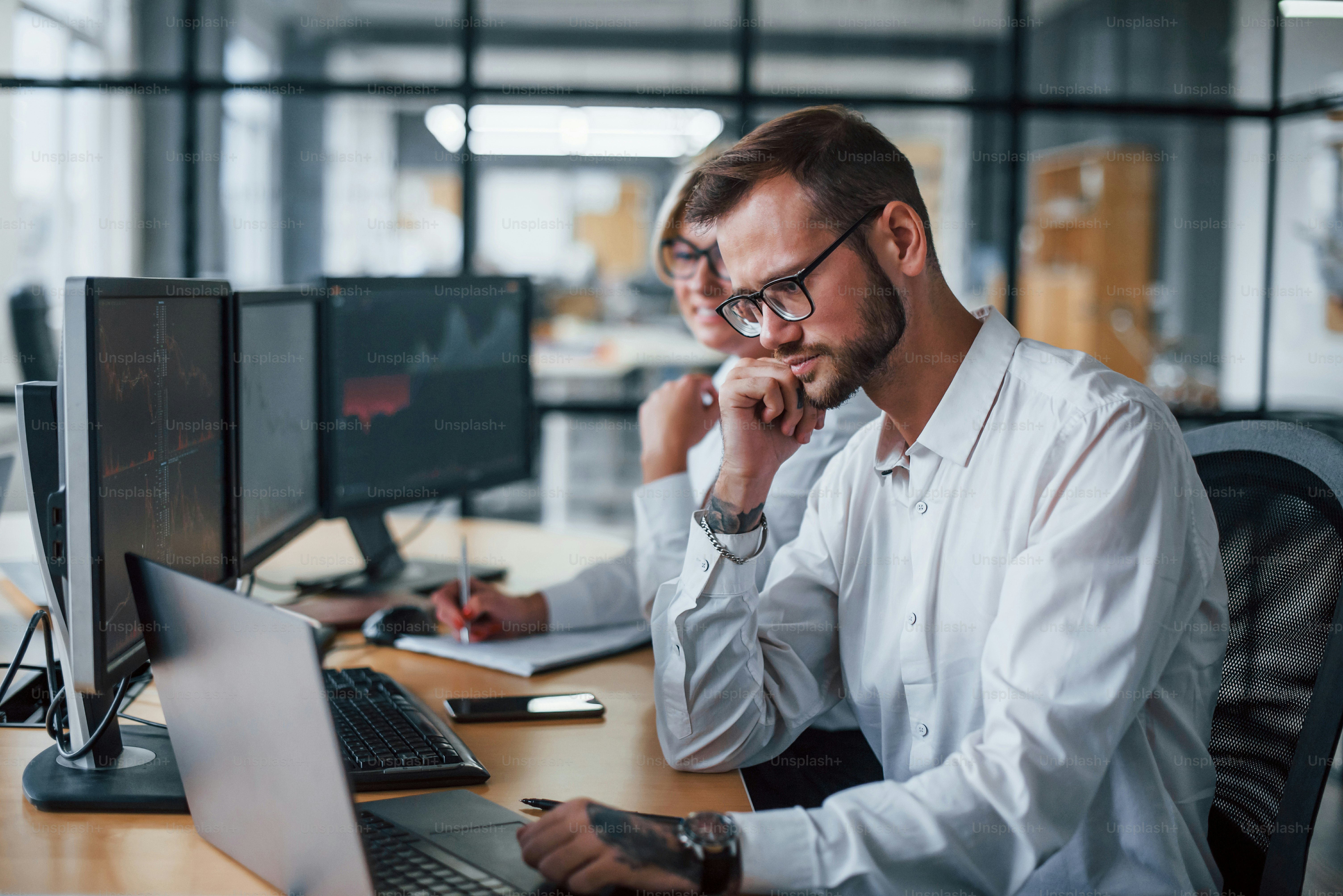 Two stockbrokers in formal clothes works in the office with financial ...