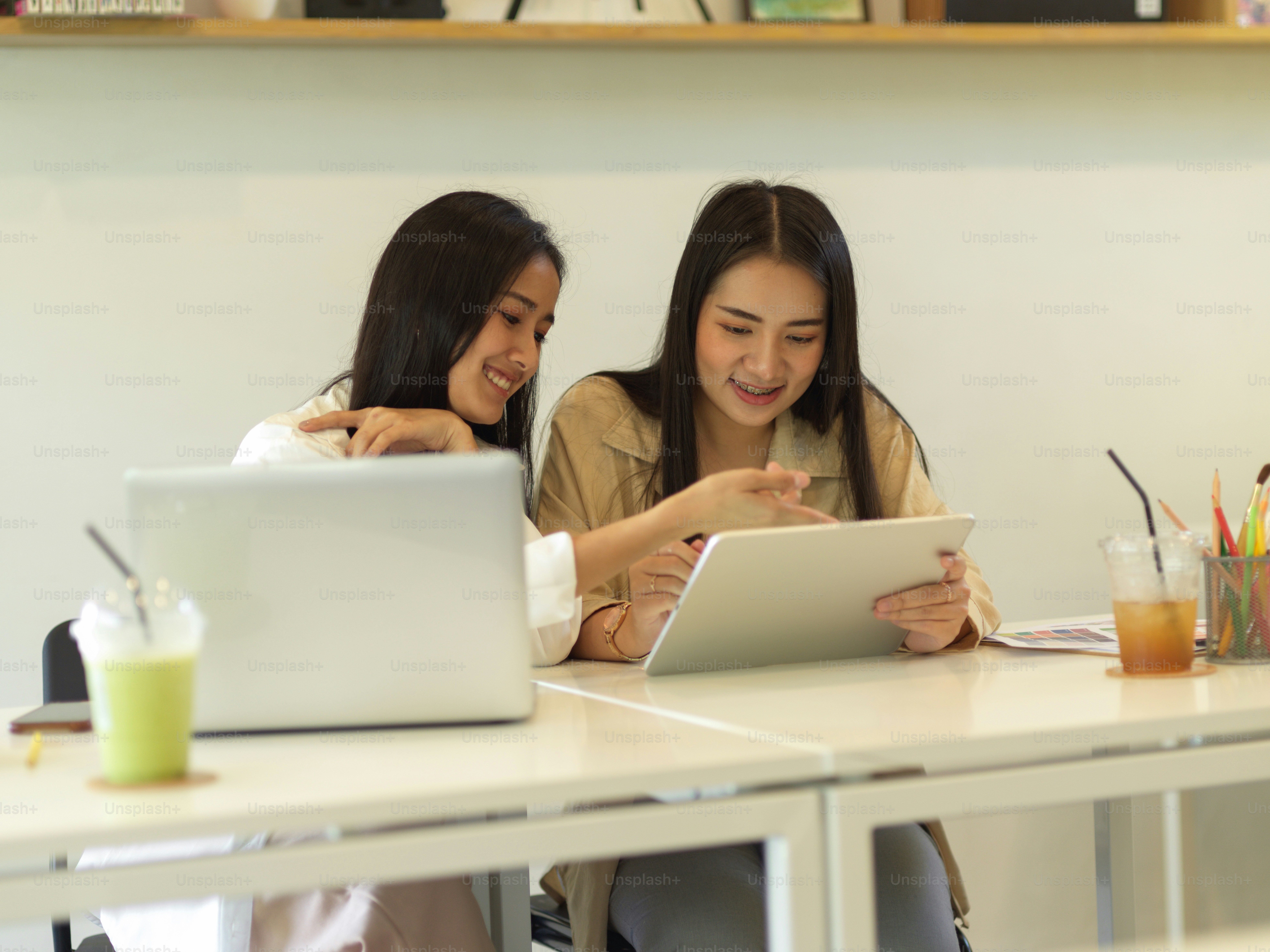 Portraits of two female students having funny conversation while doing ...
