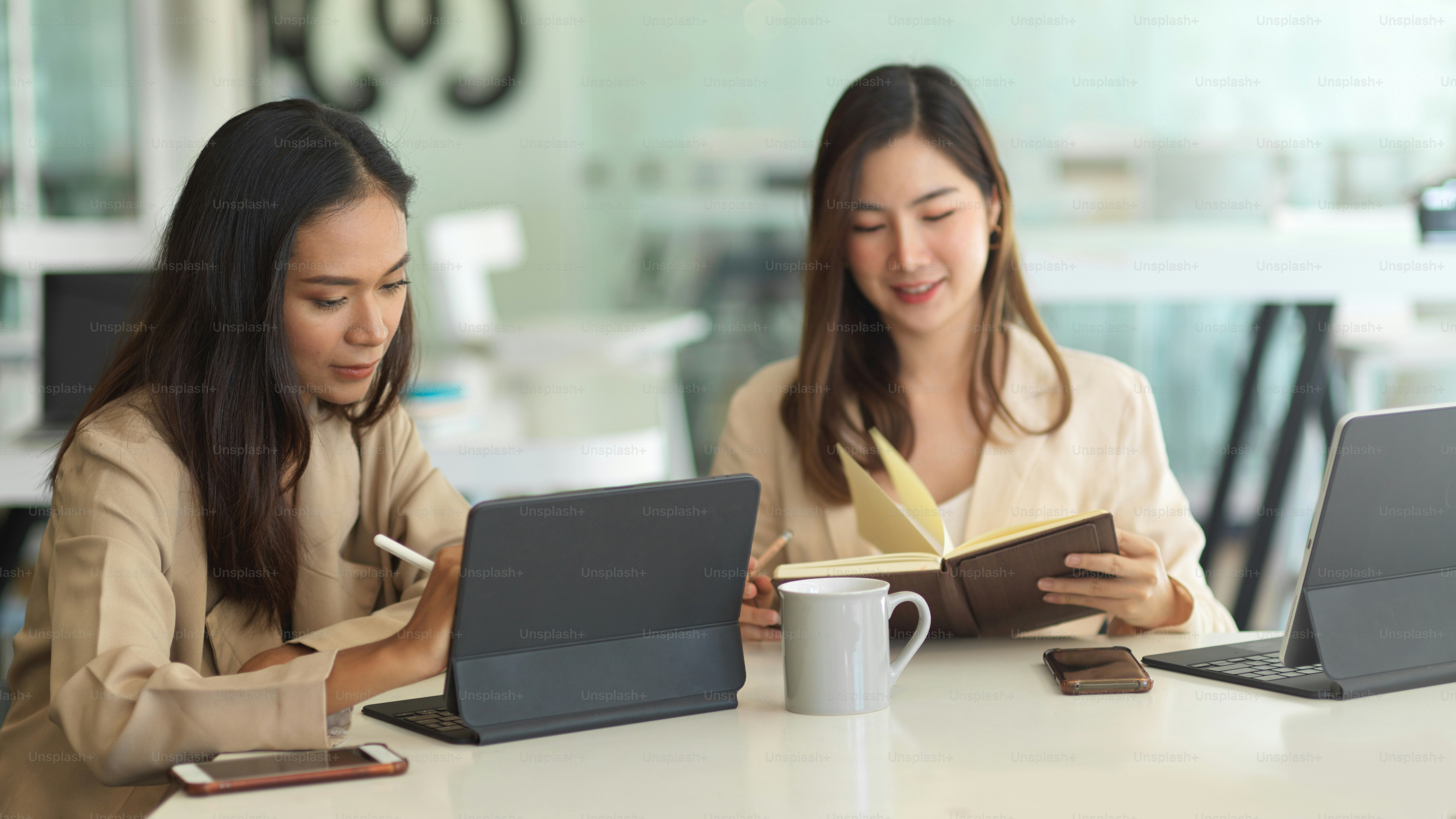 Portraits of two female office workers working on their project ...