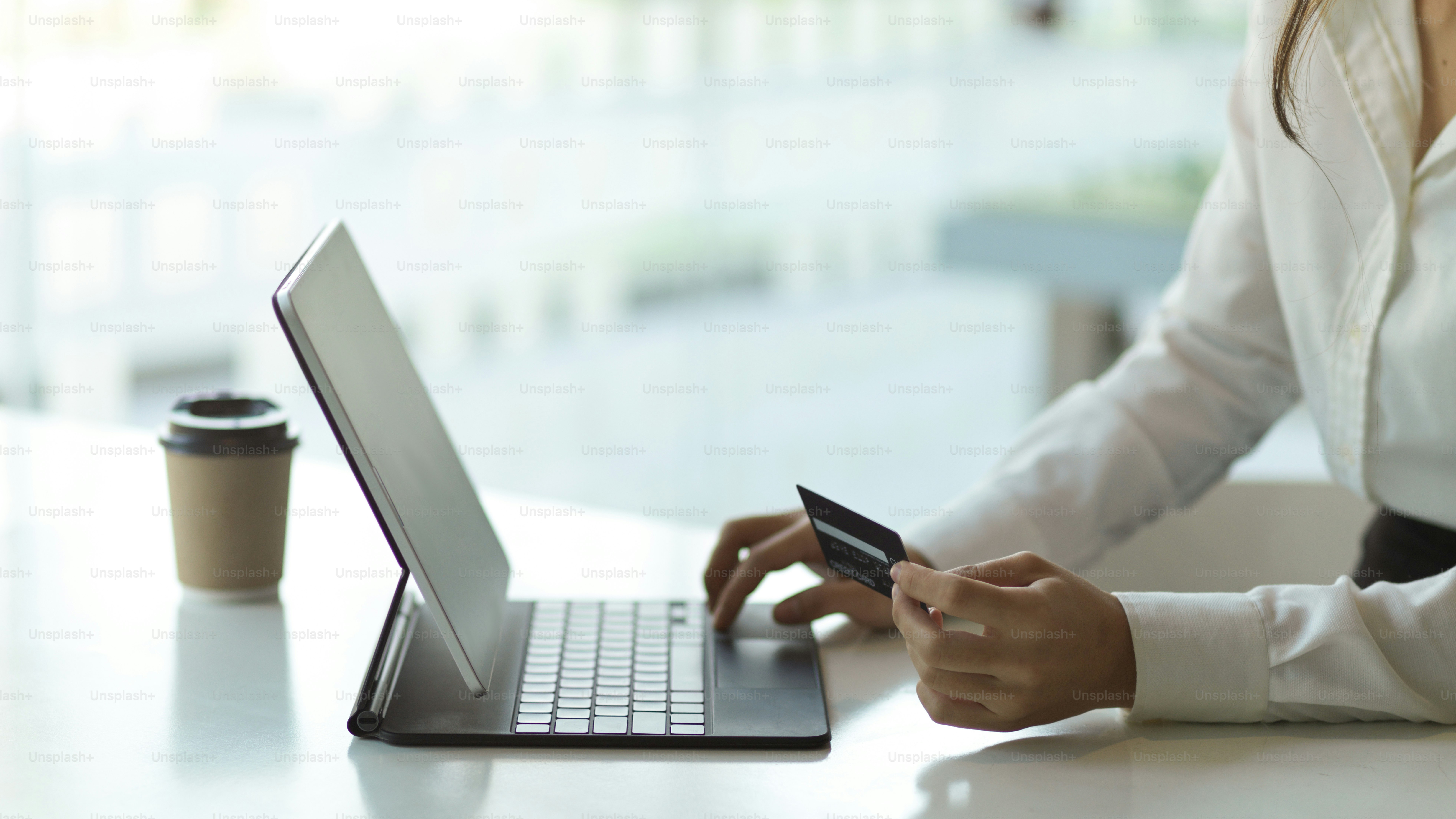 Side view of female hand holding debit card and typing on tablet ...