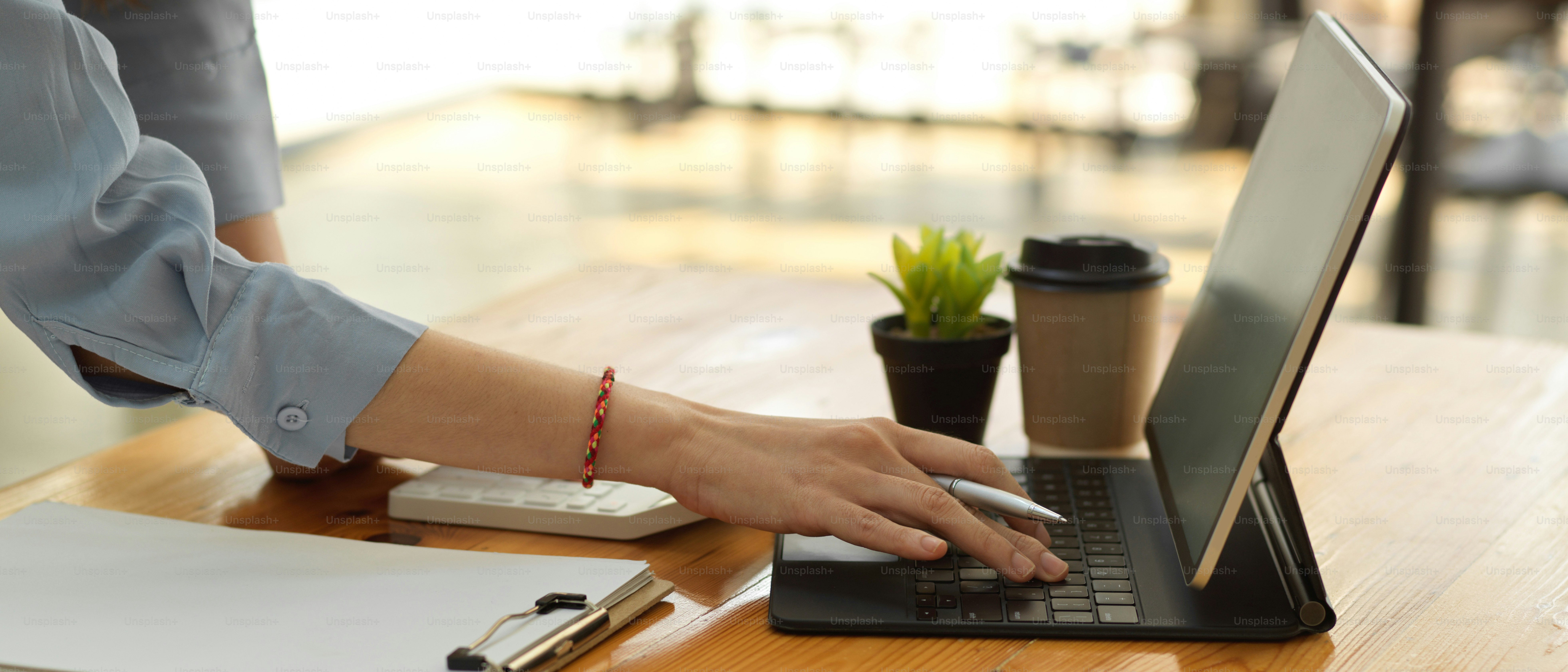 Side view of female hands typing on laptop keyboard on wooden office ...
