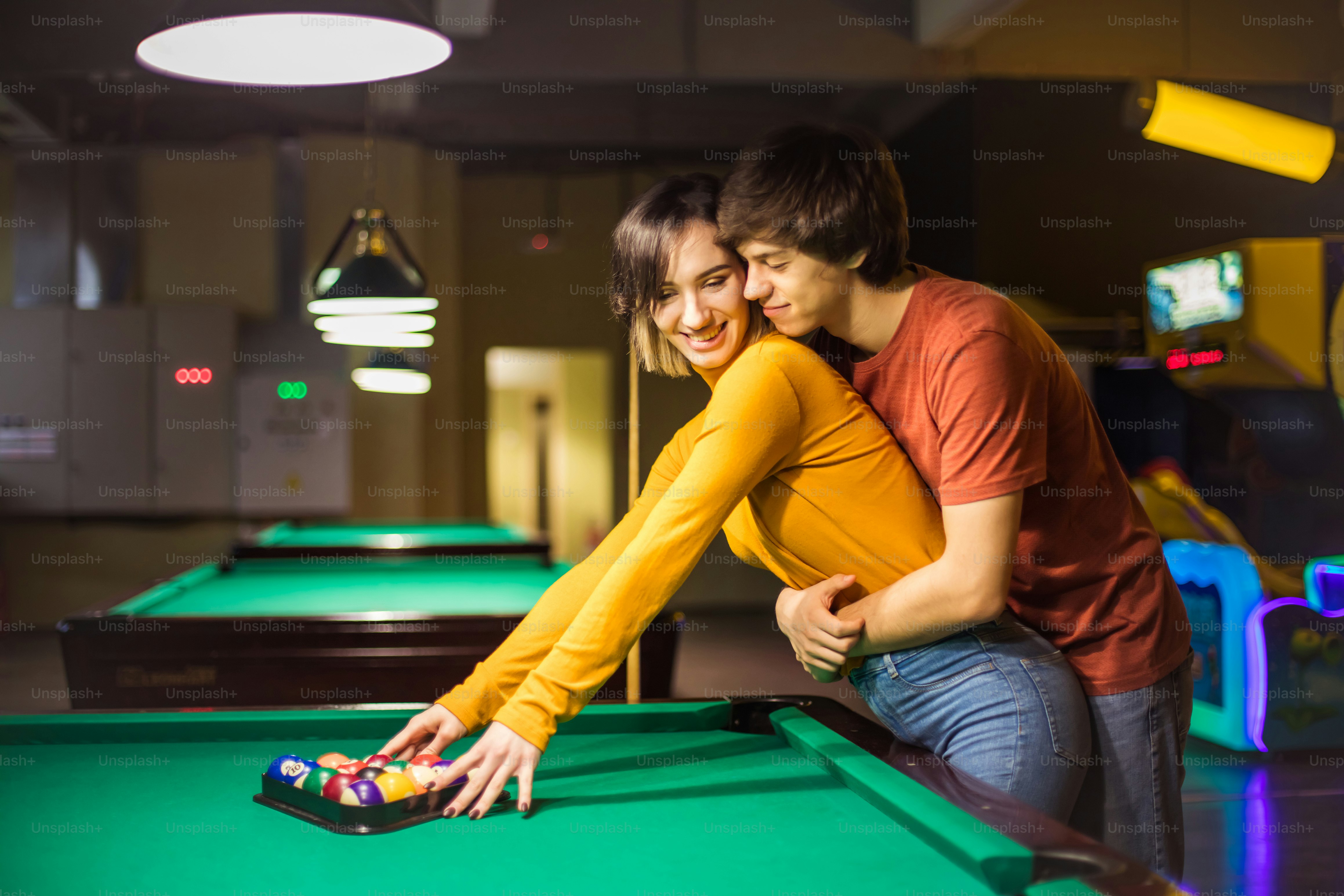 The couple is kissing in the billiard room. Couple in playroom. photo ...