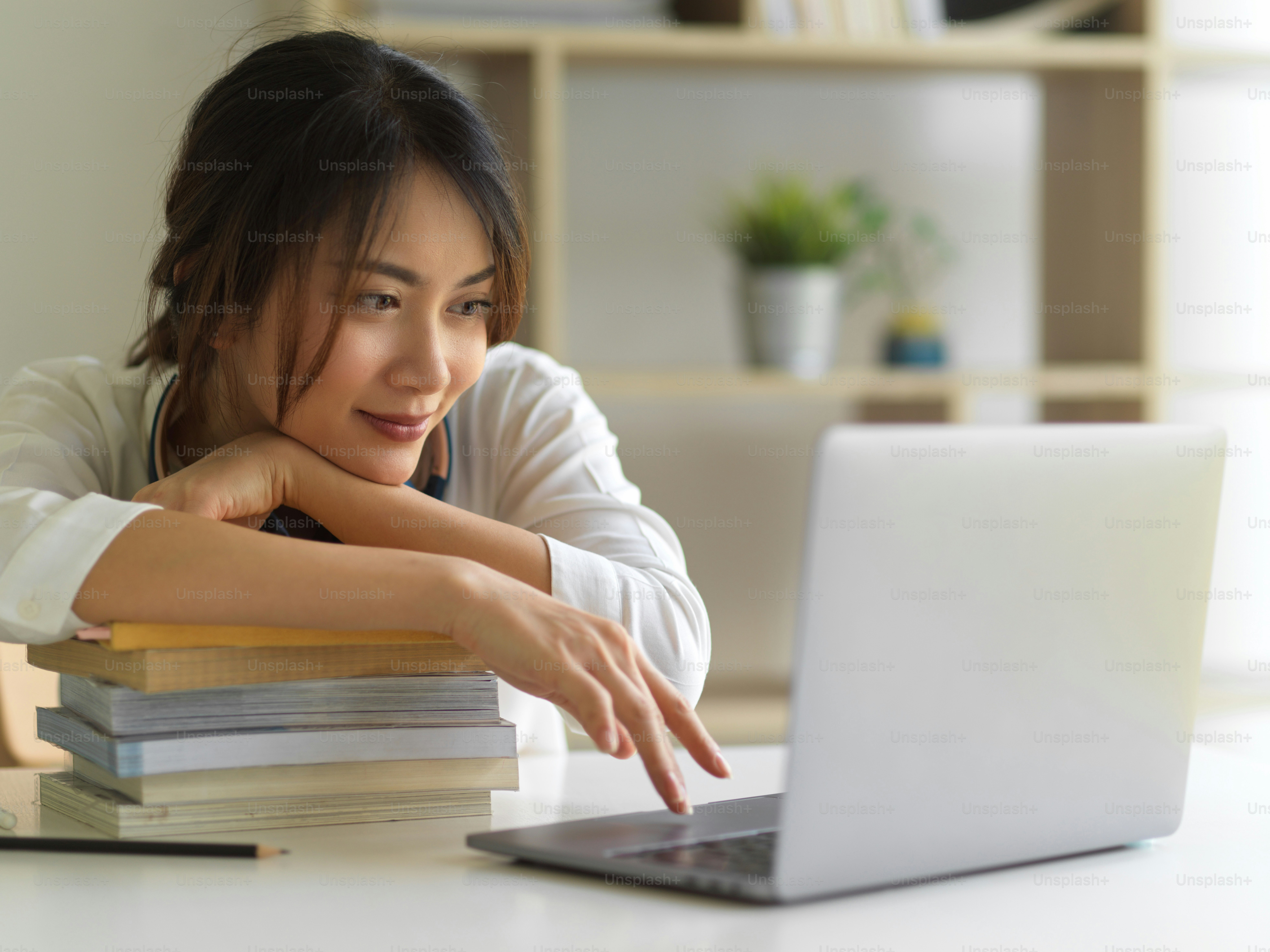 Portrait of female university student with laptop and stack of books ...