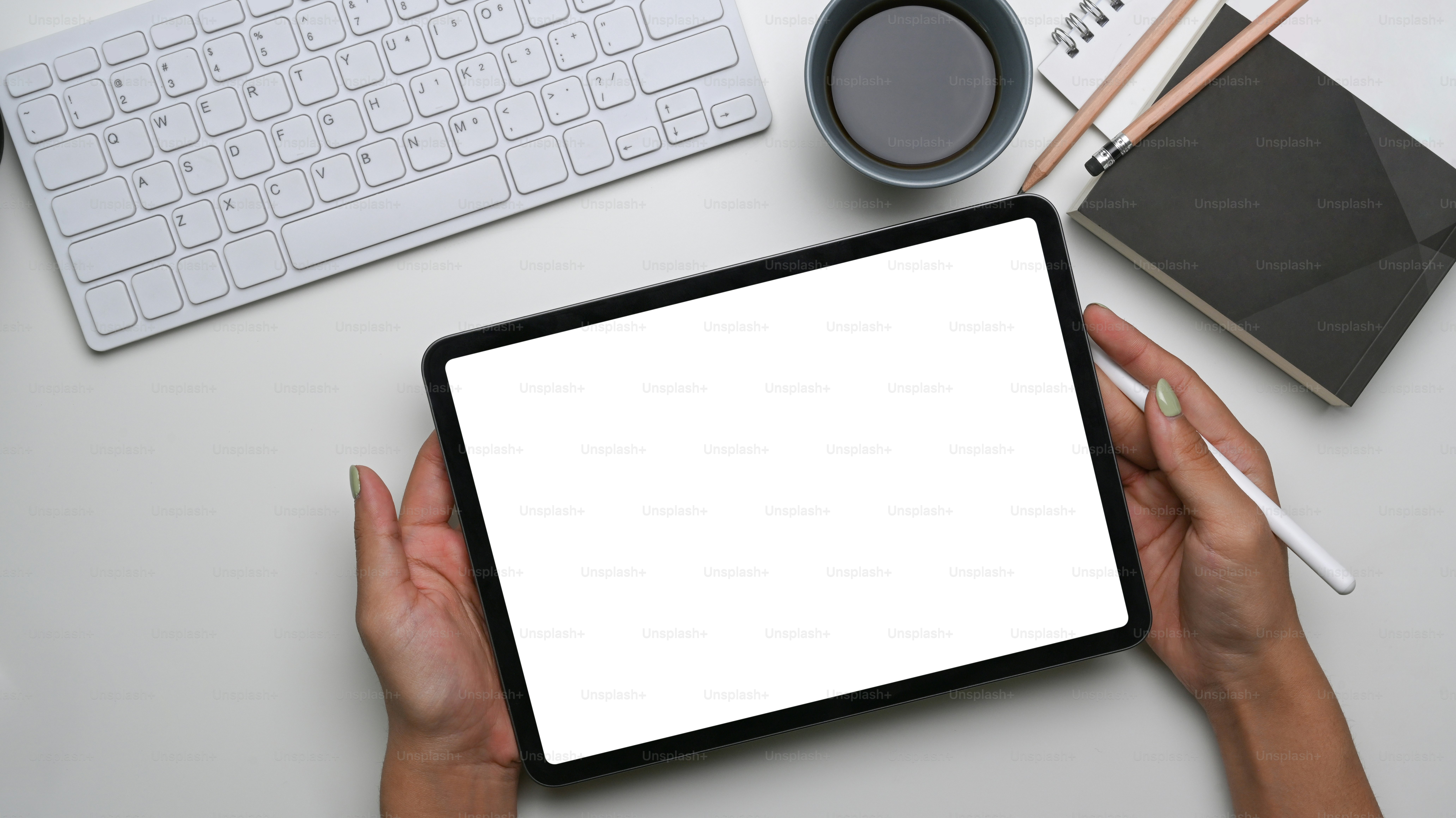 Mains de femme tenant une tablette numérique et un stylet sur une table ...