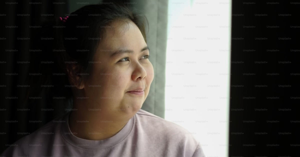 뚱뚱한 여자의 초상화는 창문 근처에 서서 웃고 시선을 돌린다 사진 Unsplash의 앉아 이미지