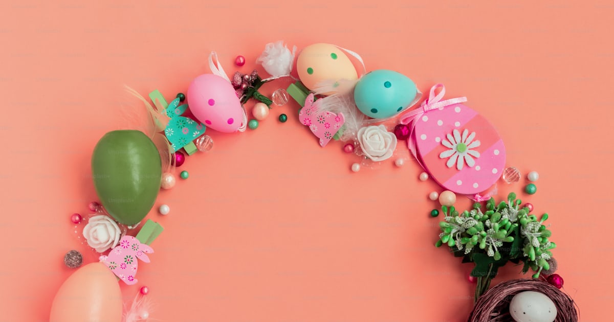 ピンクの背景にカラフルな春の花と卵で作られた円の花輪の形。 イースターのお祝いのコンセプト。上面図。フラットレイの写真 フレーム 境界