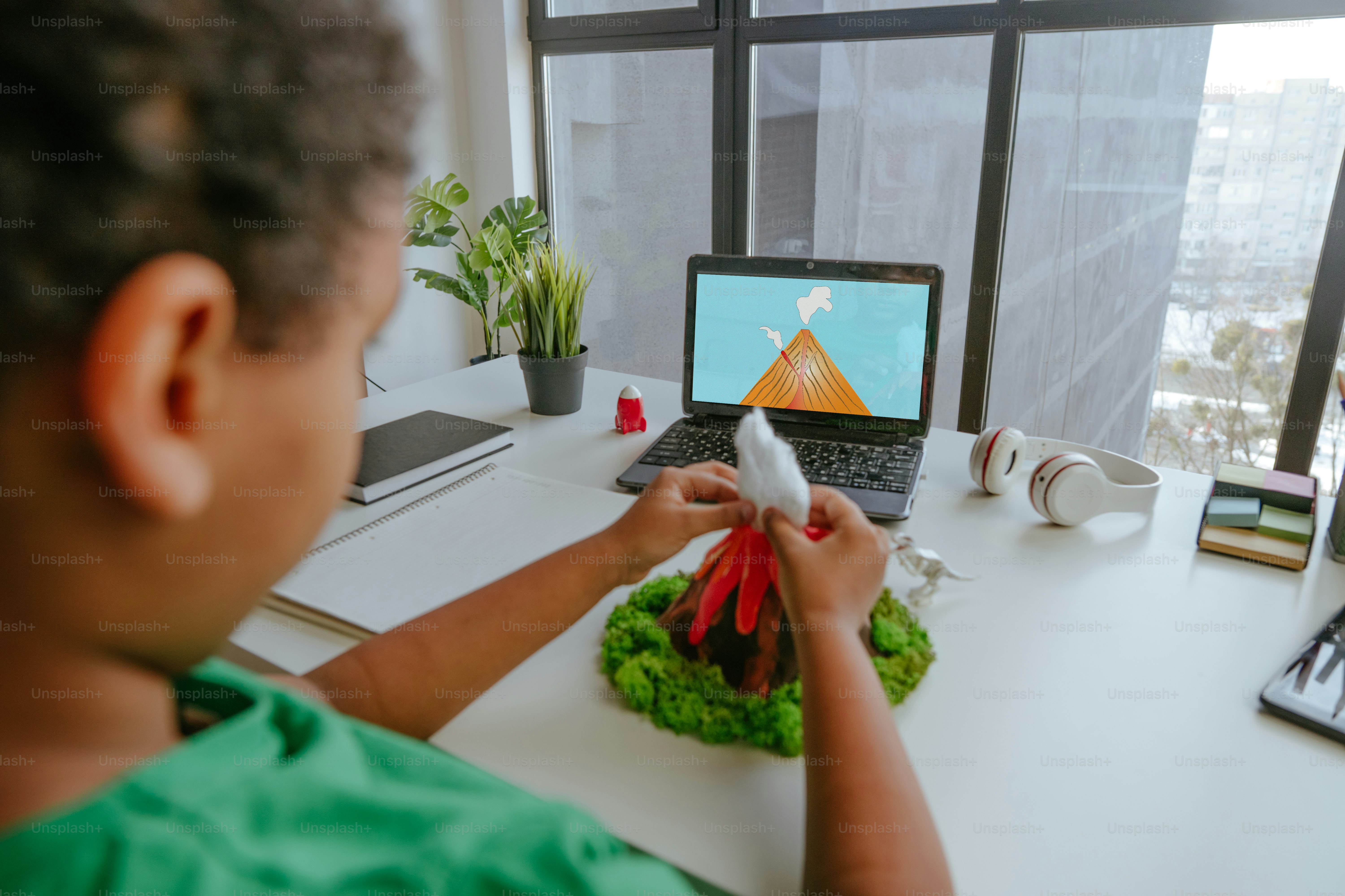 Boy watching online lesson or master class how to make volcano model ...