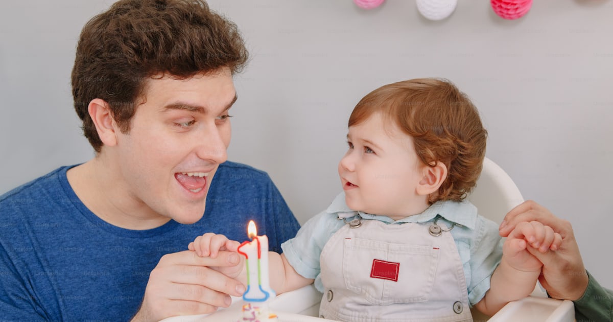 집에서 첫 번째 생일을 축하하는 아기와 함께 웃고 있는 백인 아버지 자랑스러운 부모 아빠와 아이 아이 유아 촛불 하나가 켜진