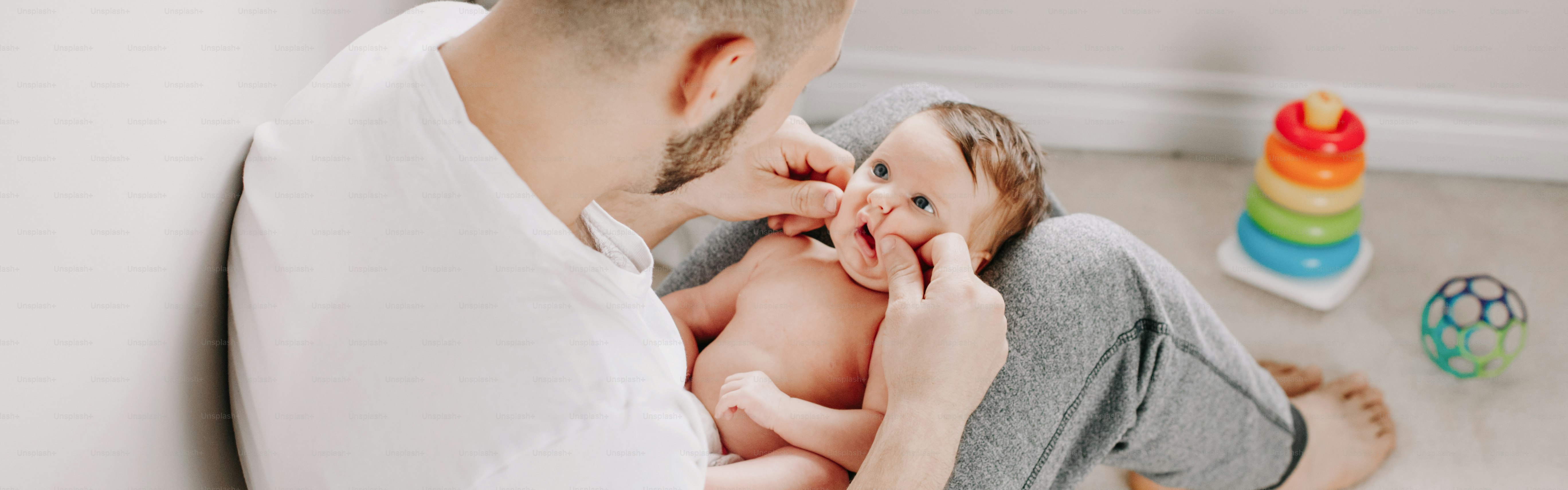 Father holding newborn baby on laps. Man parent playing with child ...