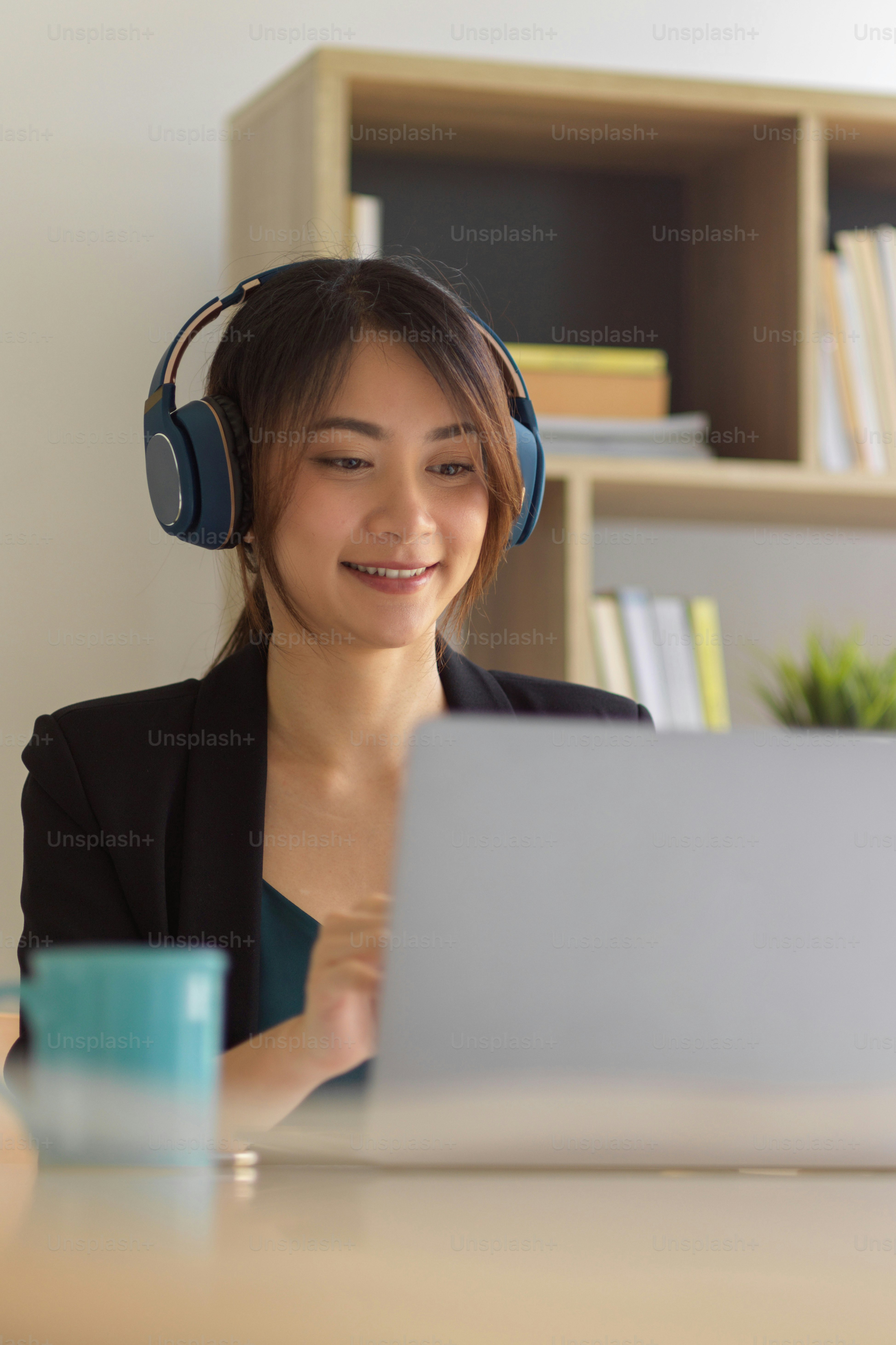 Portrait of happy businesswoman smiling and using headphone while ...