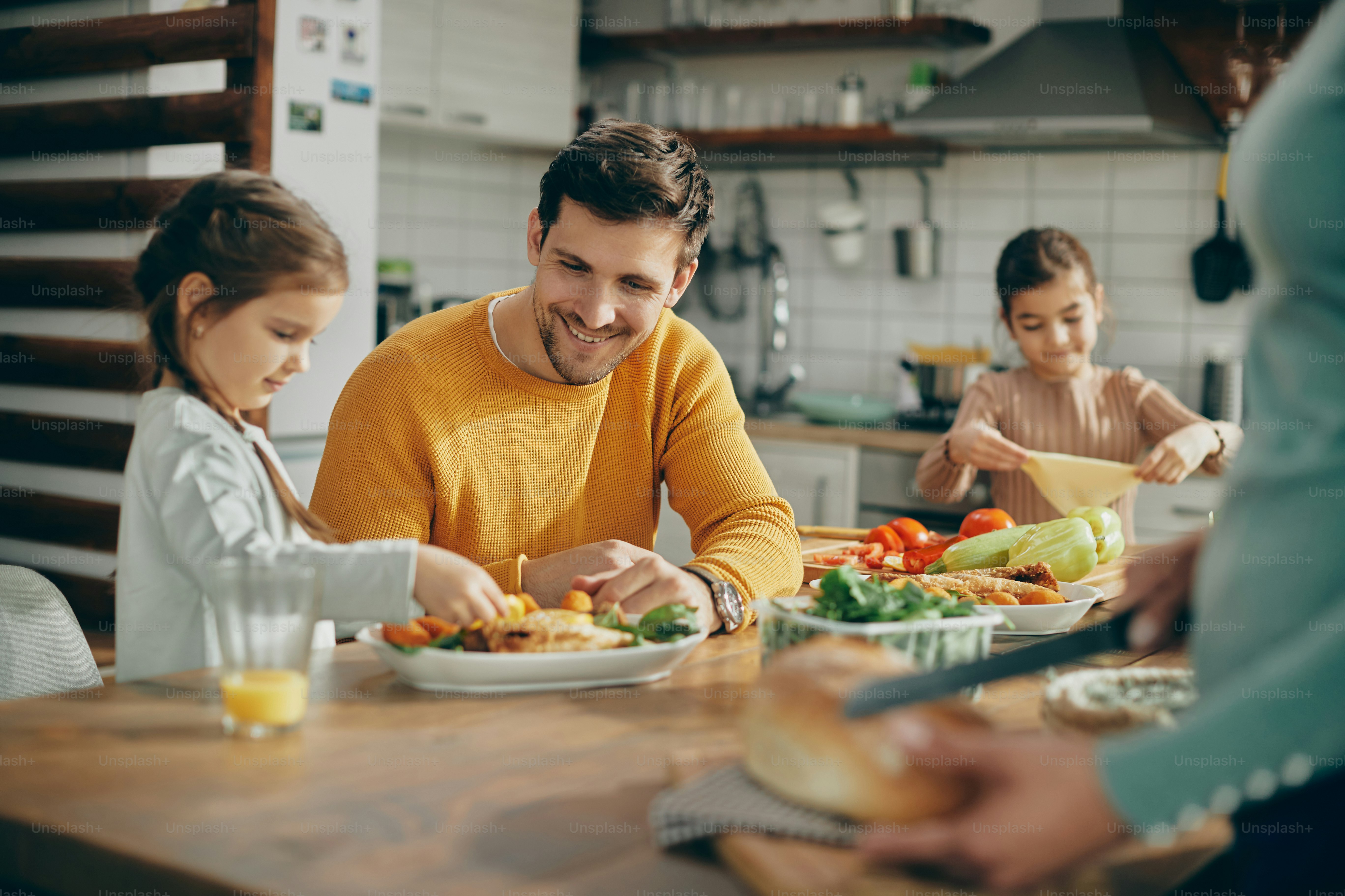 Happy family preparing dining table for lunch at home. Focus is on ...