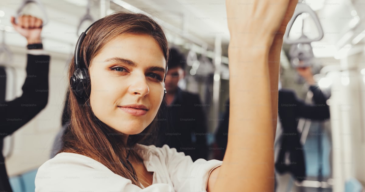 Beautiful Young Woman Passenger Standing With Headphones And While Shirt In The Modern Subway