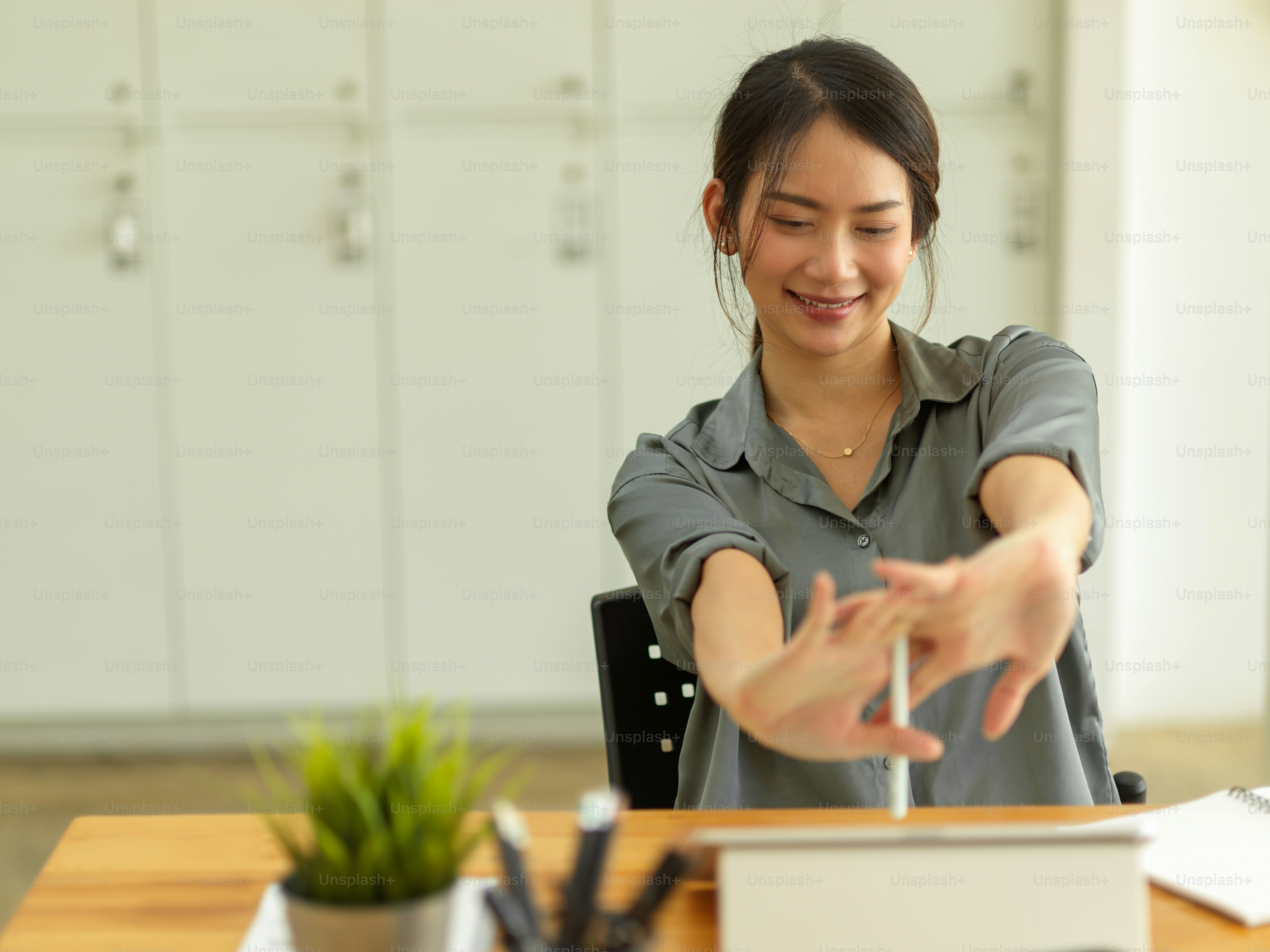 Portrait of female office worker stretching her arms, relaxing in ...