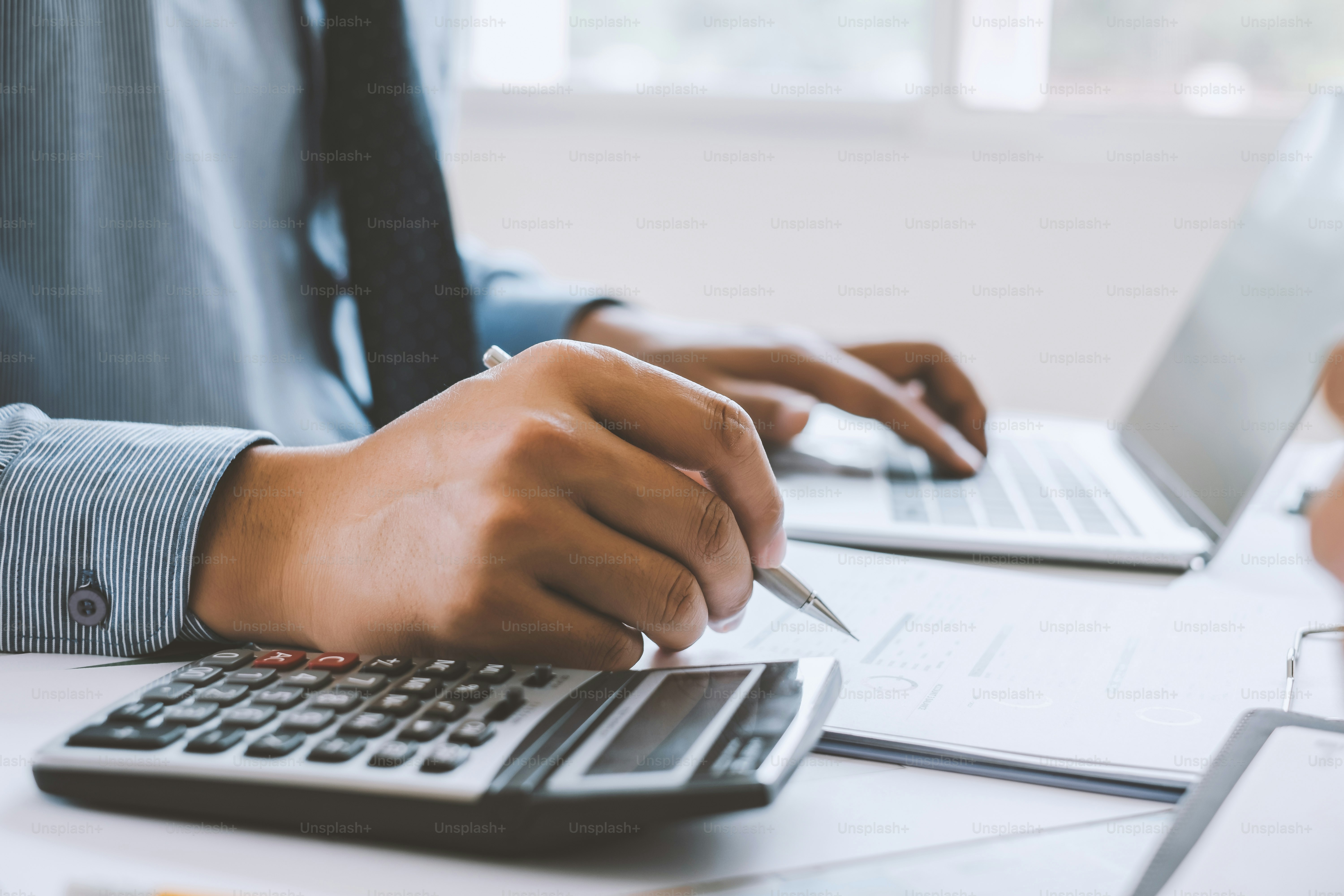 Businessman taking note and using calculator during a business meeting ...