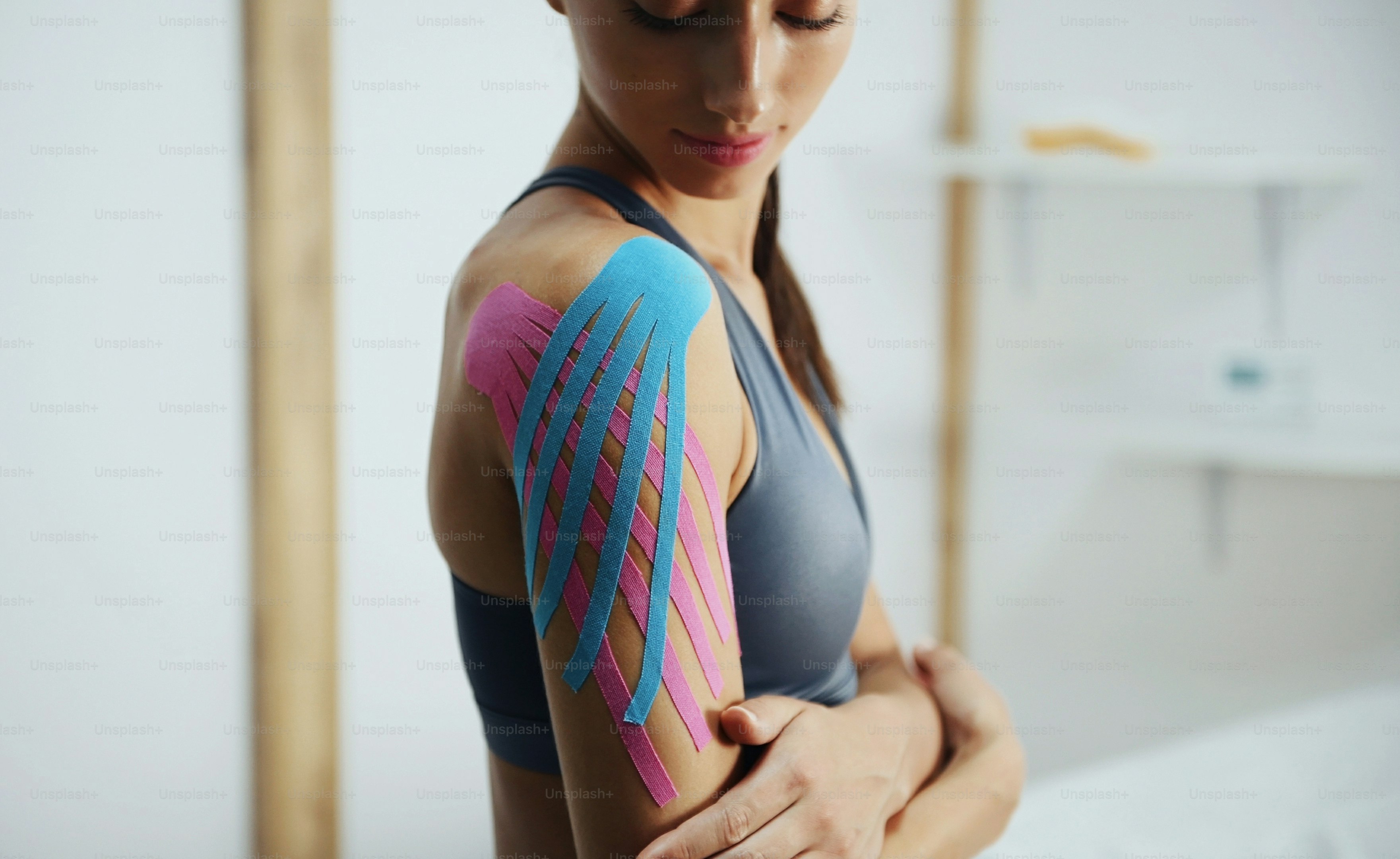 Sportive woman sits indoors with kinesio tape on her shoulder. photo – Ukraine Image on Unsplash