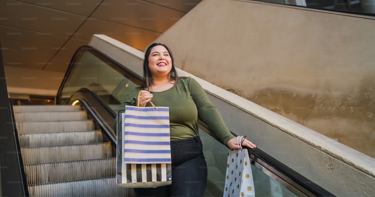 ショッピングモールで買い物をしながら買い物袋を持っている若いプラスサイズの女性の肖像画。ショッピングとセールのコンセプト。の写真 写真撮影