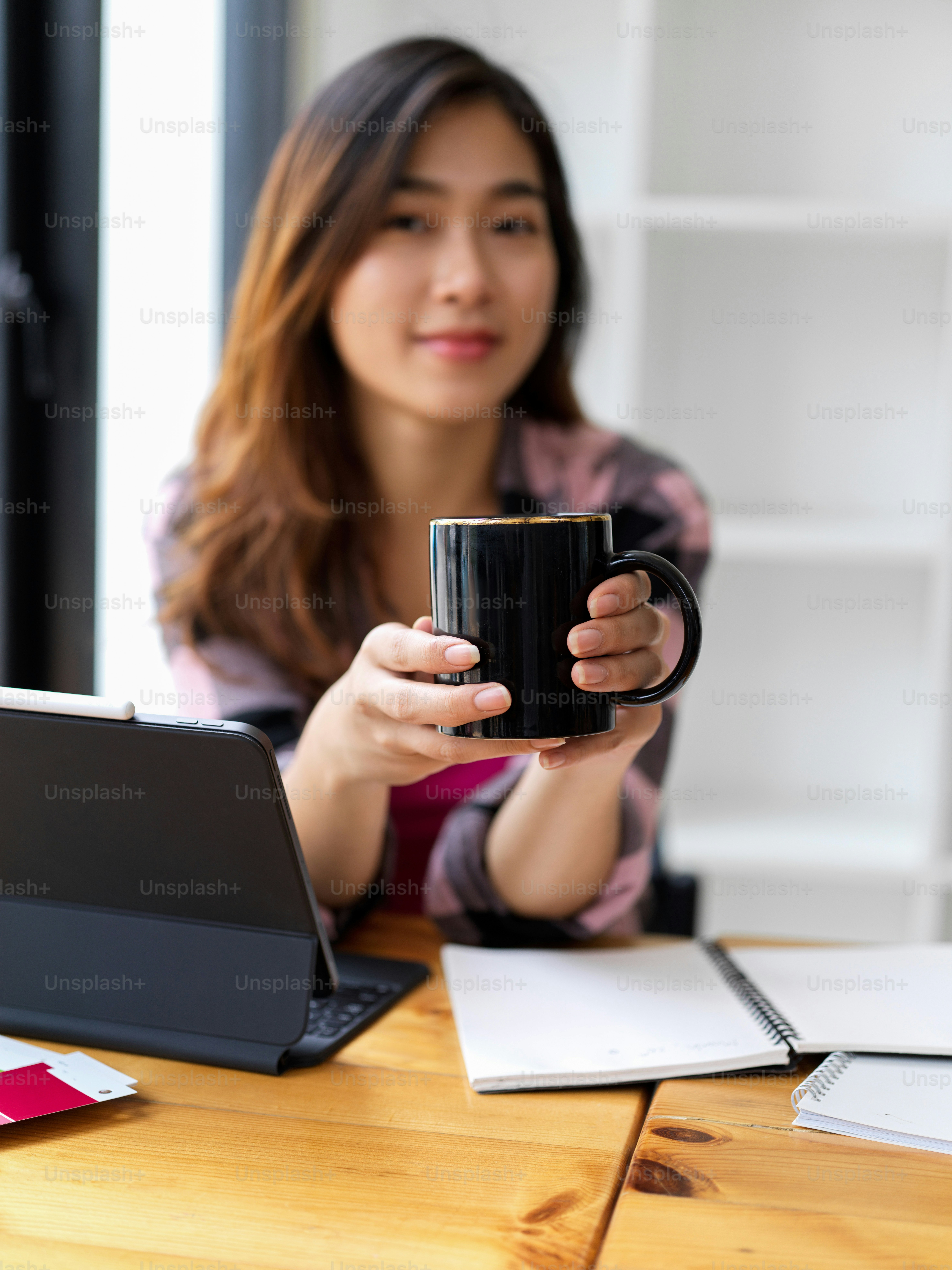 Cropped shot of female teenager holding coffee cup while relaxing at study table photo ...
