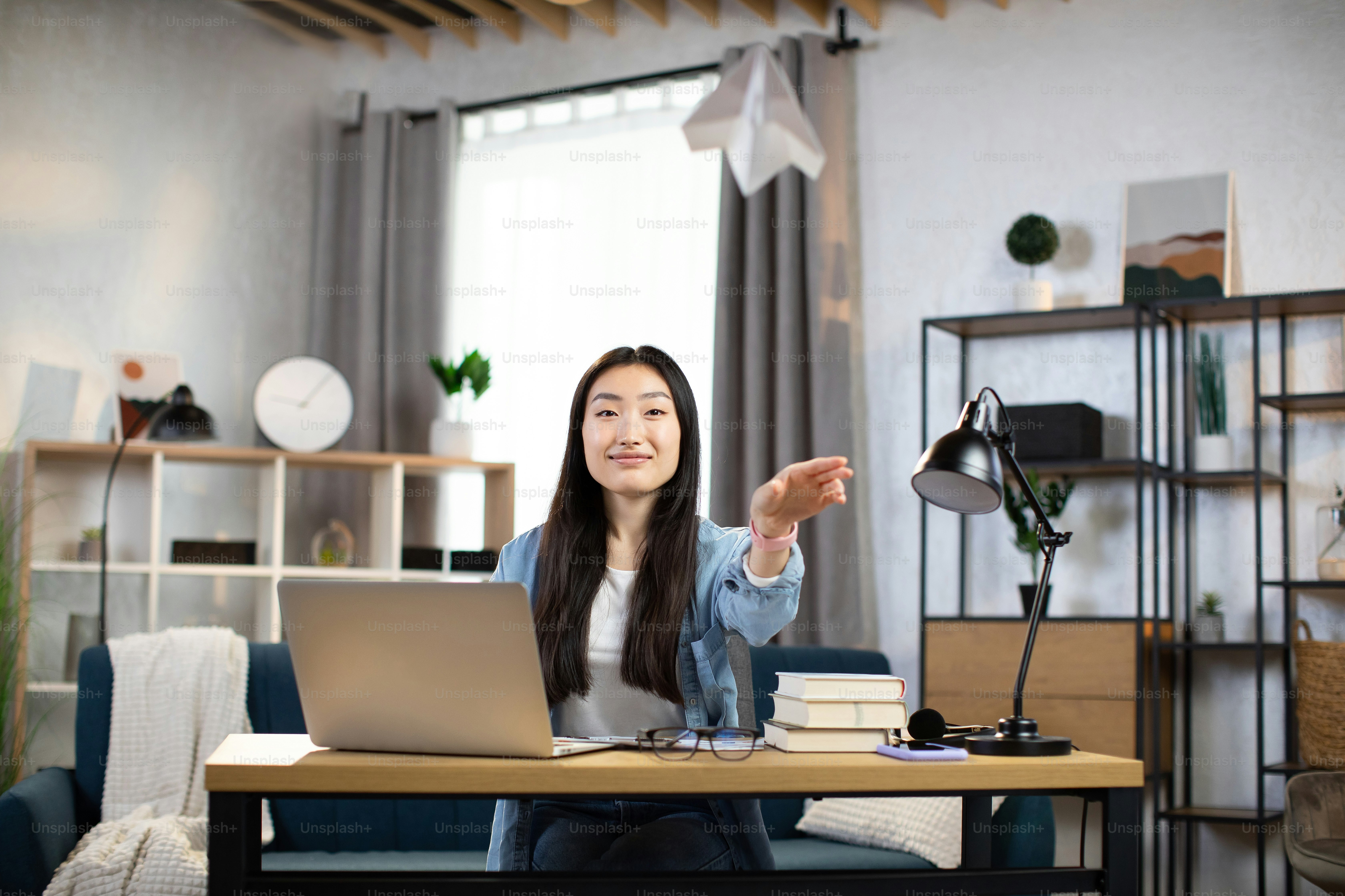 Smiling female freelancer playing with paper plane while working from ...