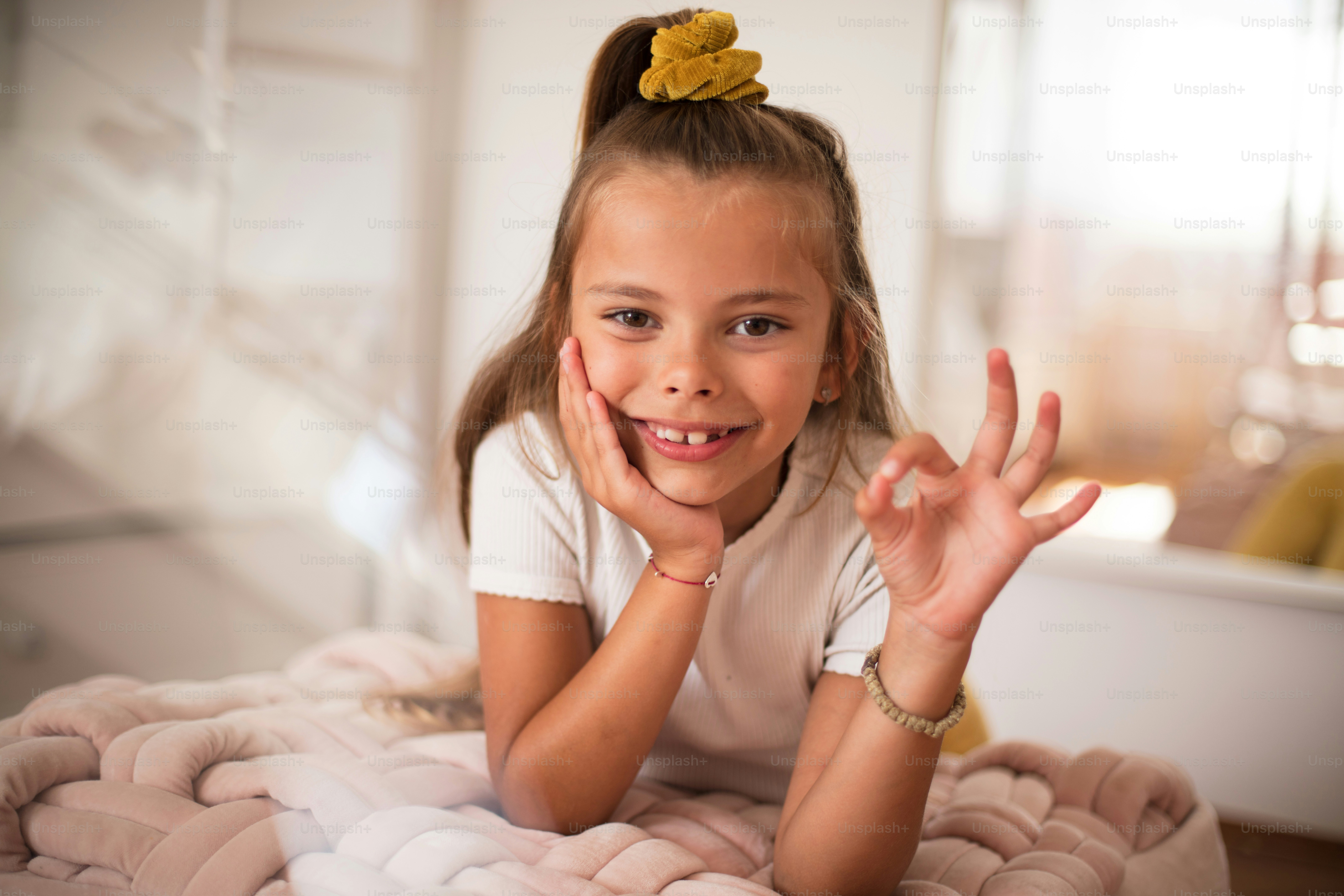Portrait of smiling little girl in her bedroom. Looking at camera ...