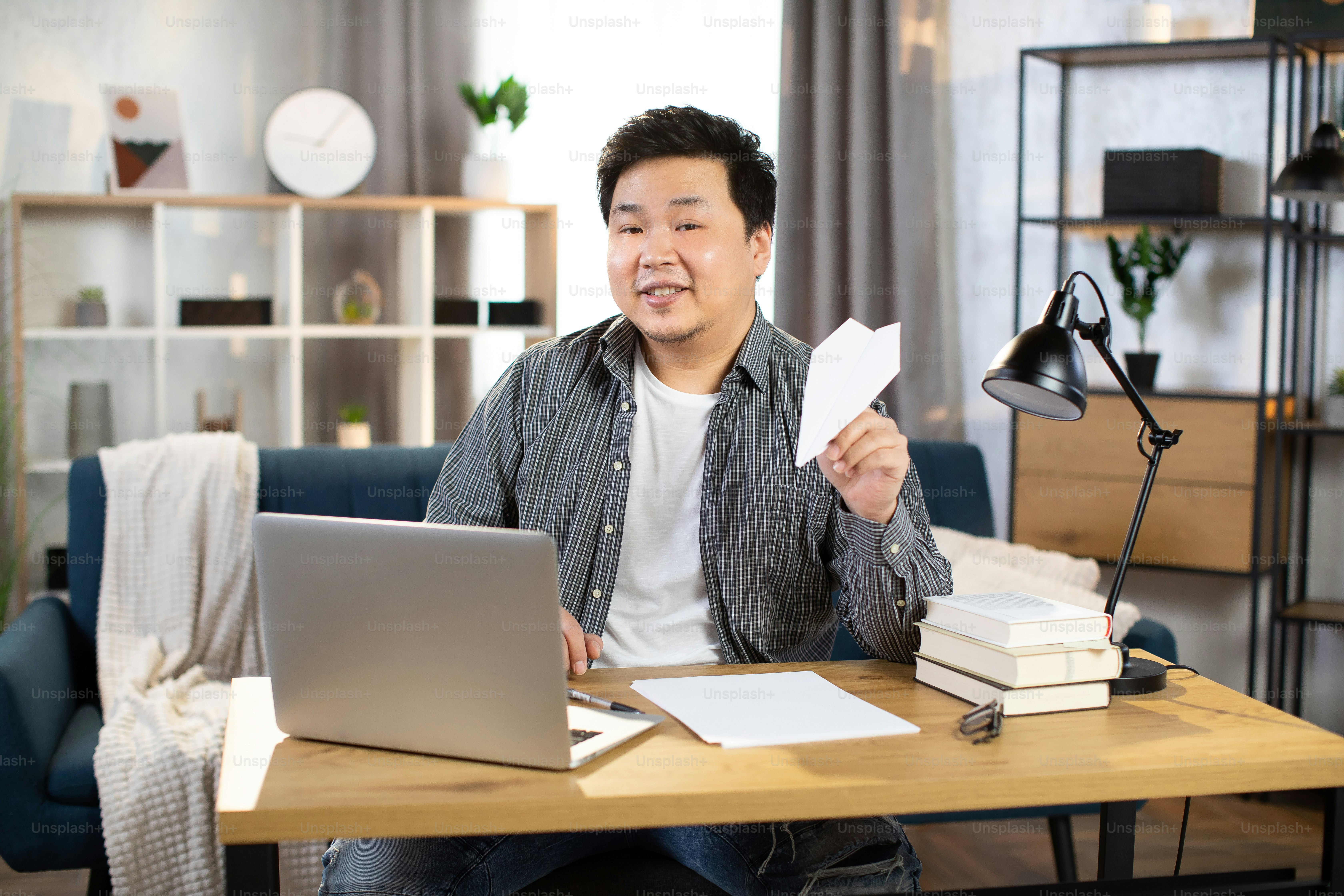 Smiling asian chinese freelancer sitting at desk with wireless laptop ...