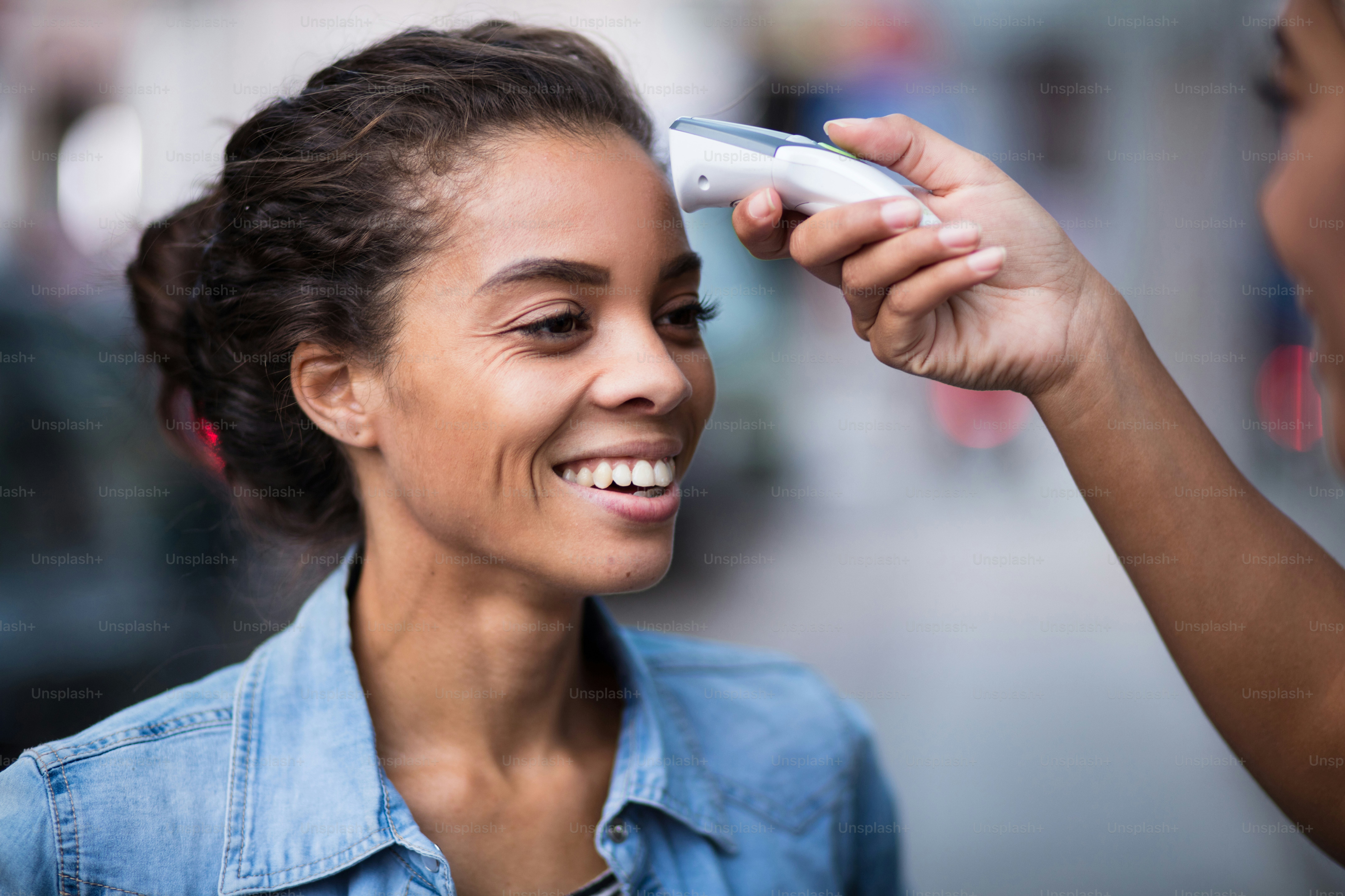 Checking body temperature for Covid 19 in a public place. Focus is on ...