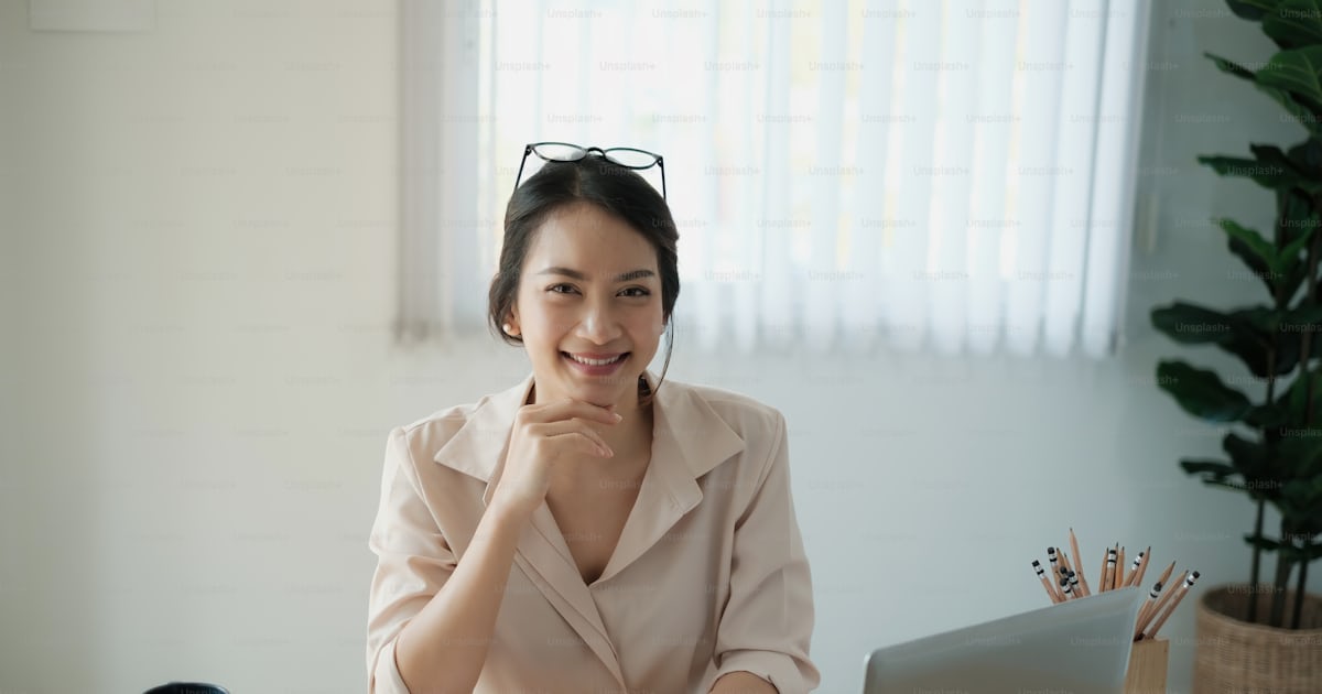 그녀의 사무실에 앉아 있는 행복한 여자의 초상화 매력적인 젊은 자신감 있는 비즈니스 여성 또는 회계사가 웃고 있으며 그녀의 큰