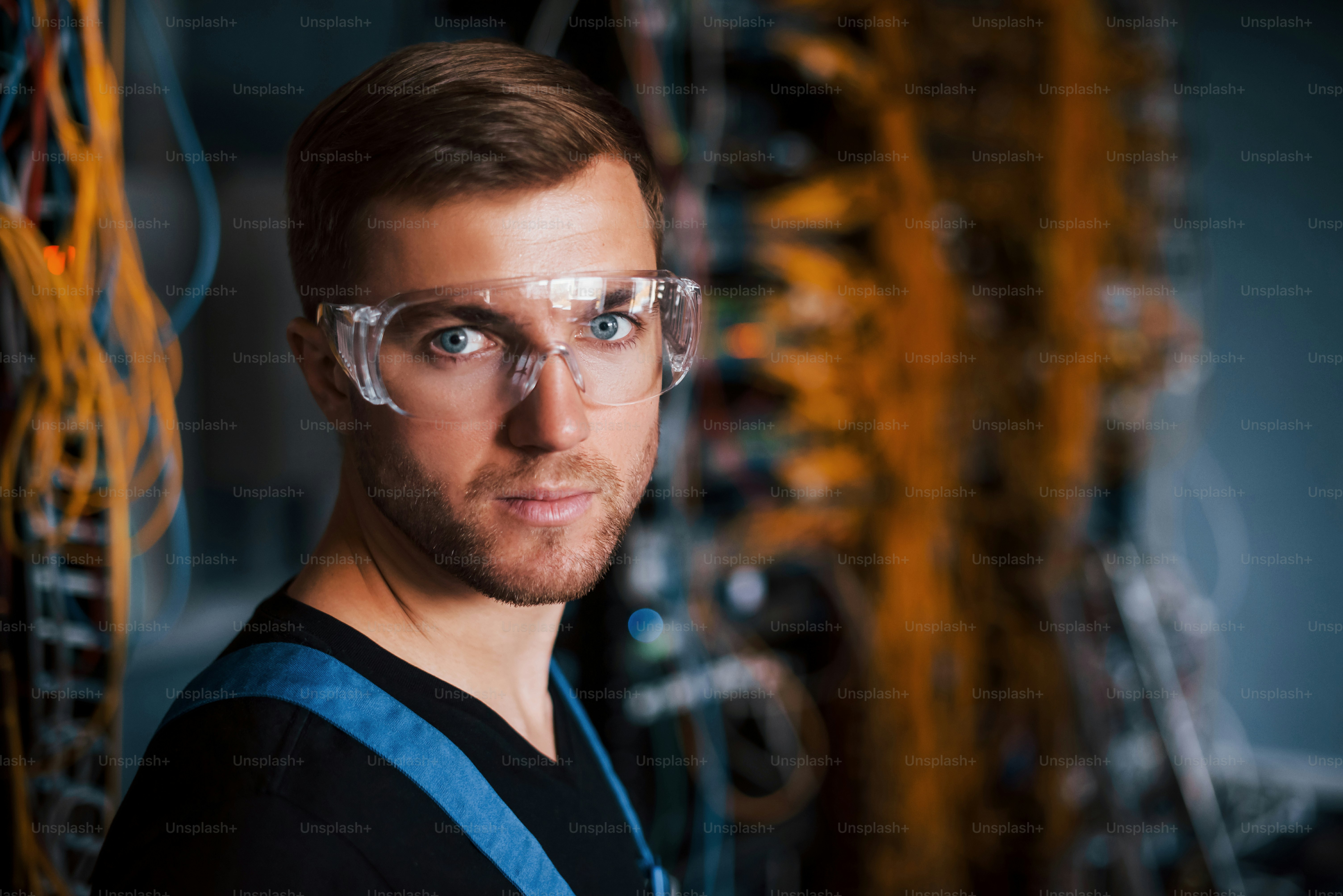 Young man in uniform works with internet equipment and wires in server ...